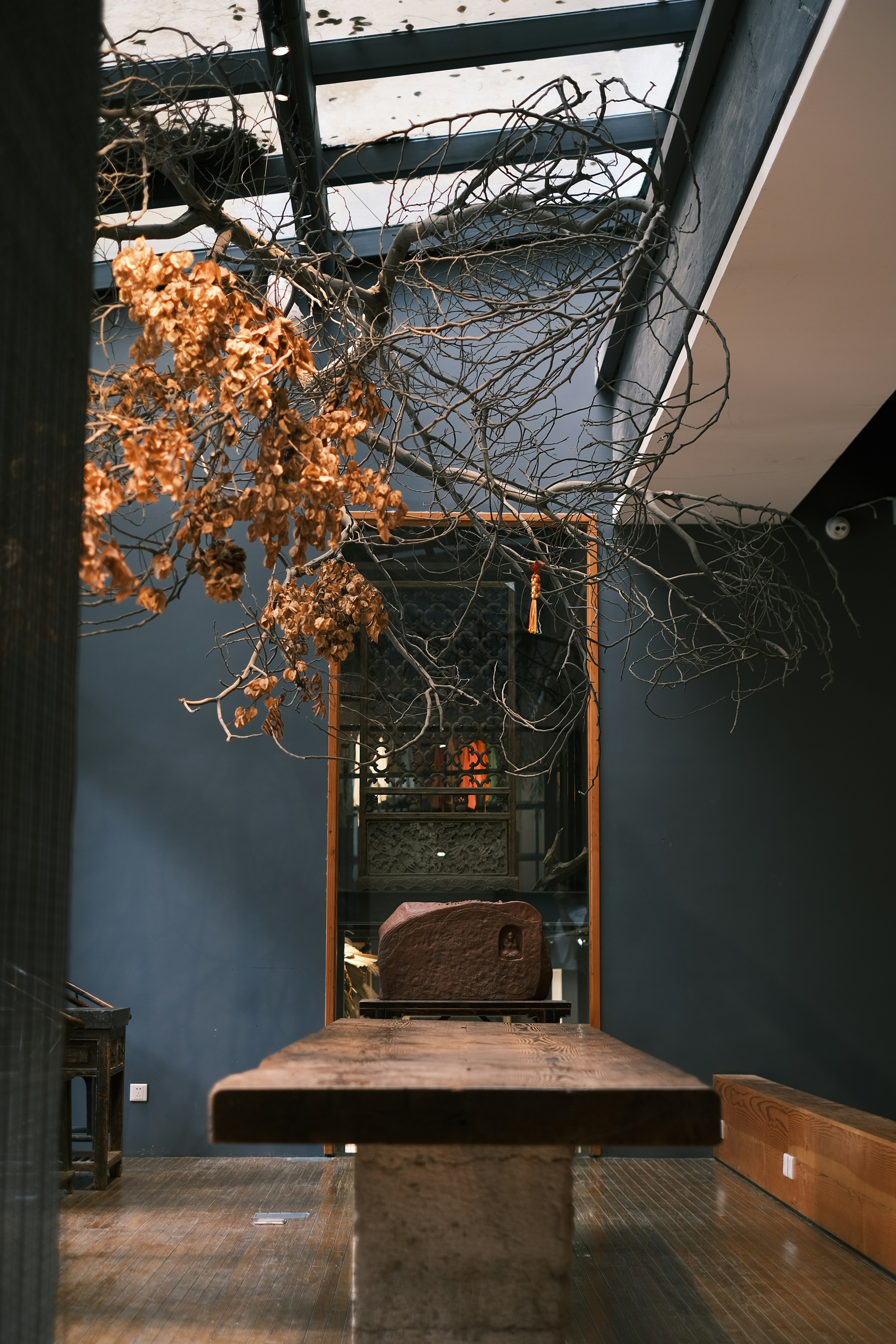 Blue Corridor Reverie: A Weathered Table Draws the Eye to a Doorway Framed by Withered Branches