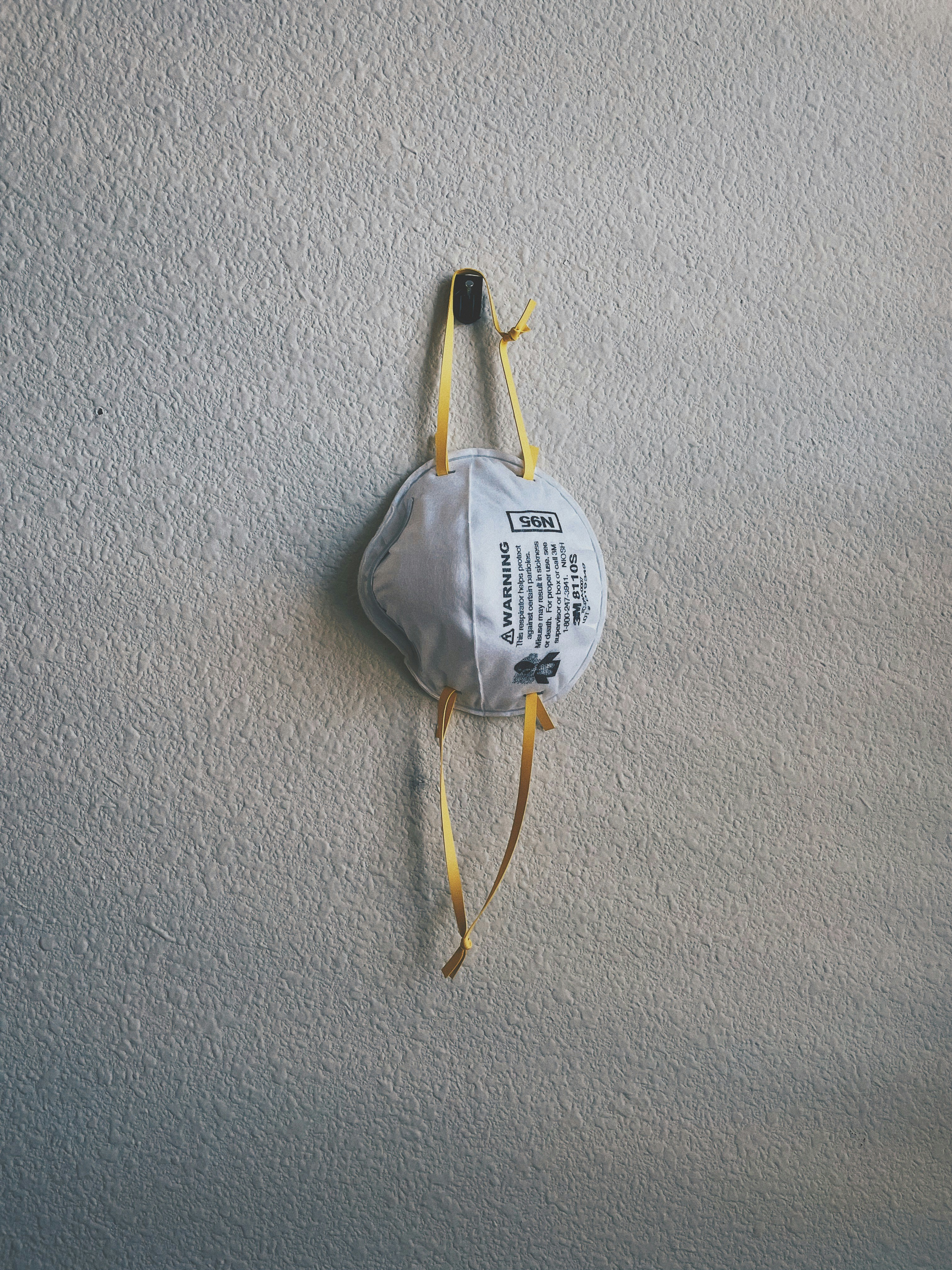 Quiet Pendant: A lone protective mask on a weathered wall