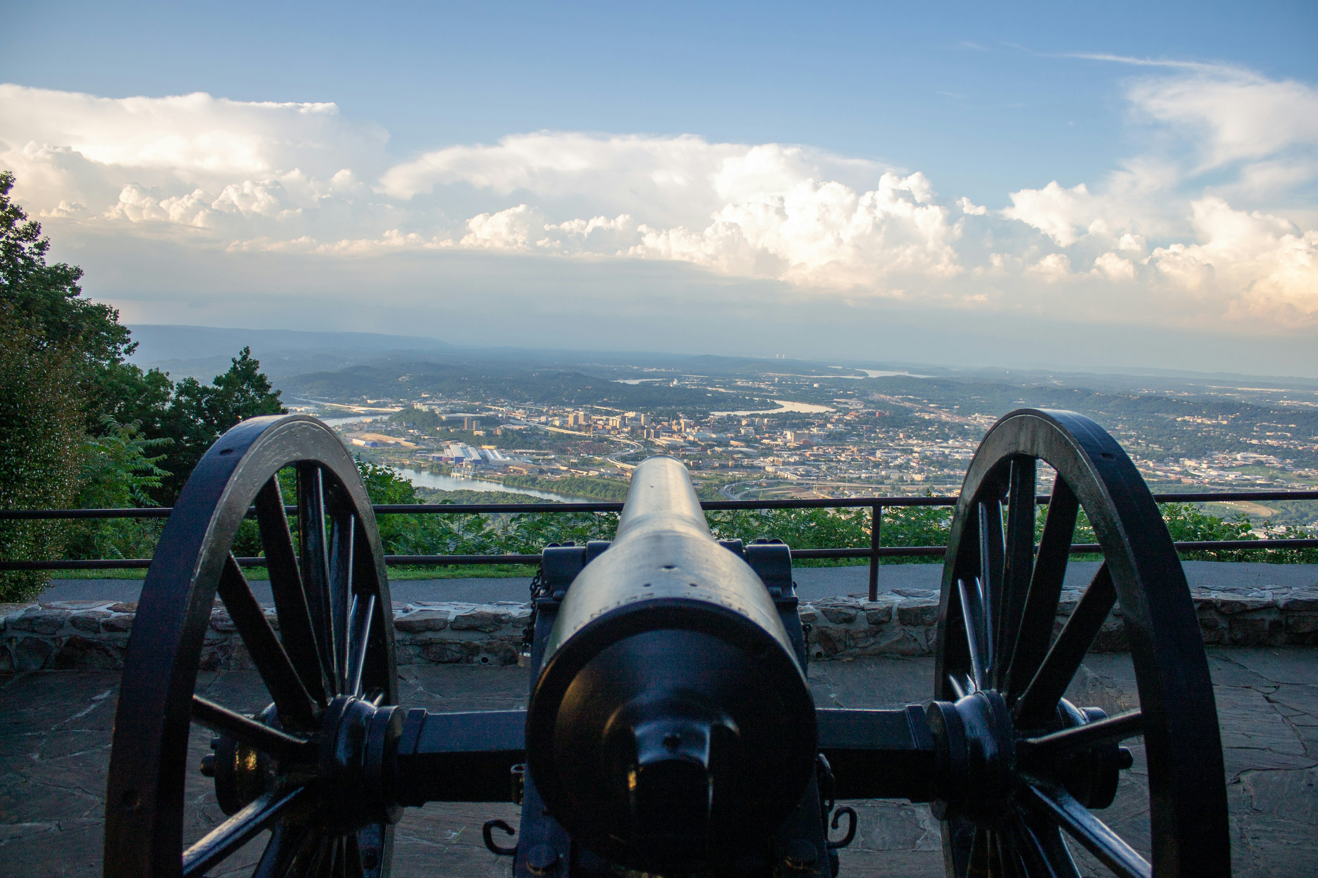 Iron Sentinel Overlook: A Cannon Framing the City Beneath Broad Skies