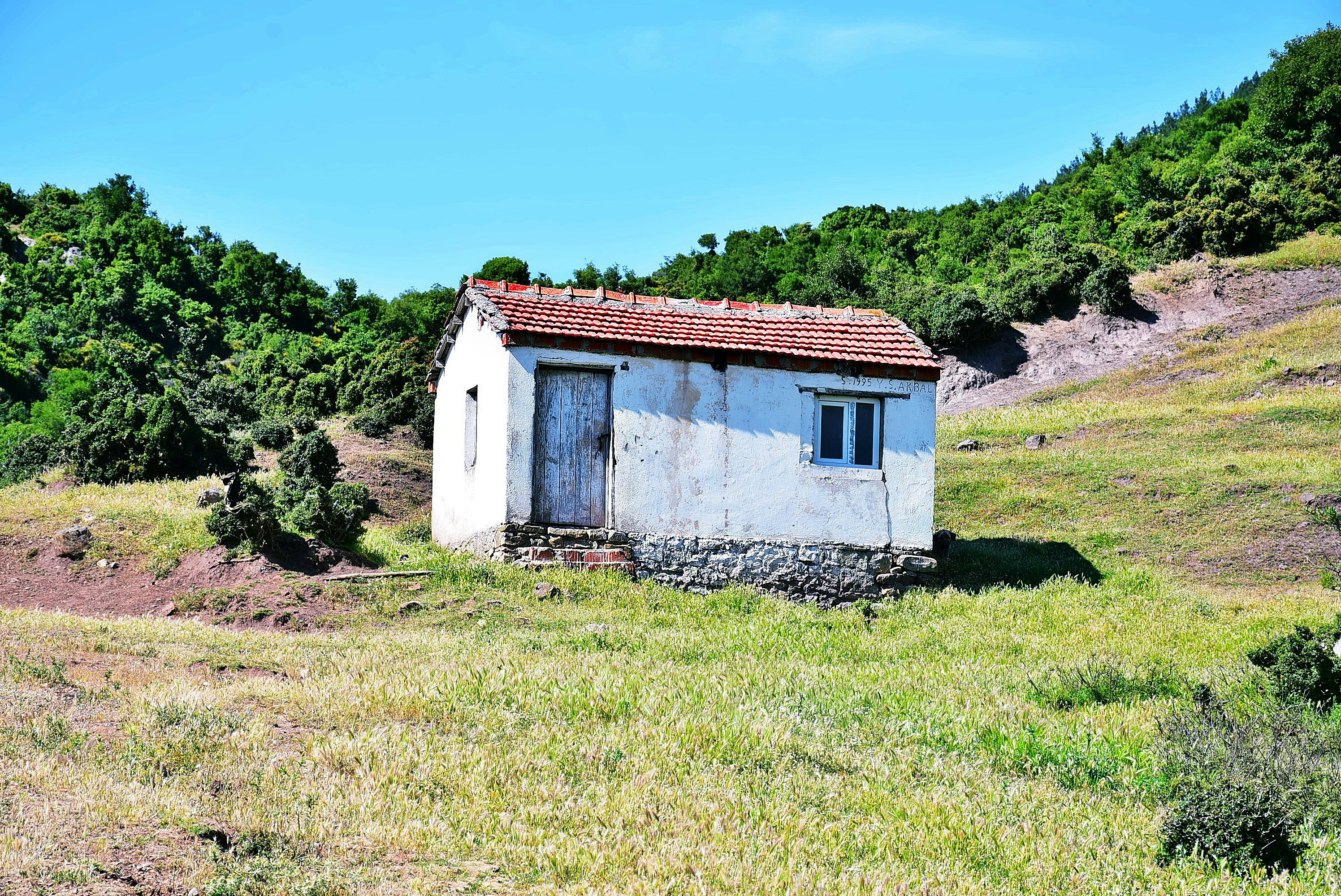 White Cottage on a Gentle Hill under a Bright Blue Sky