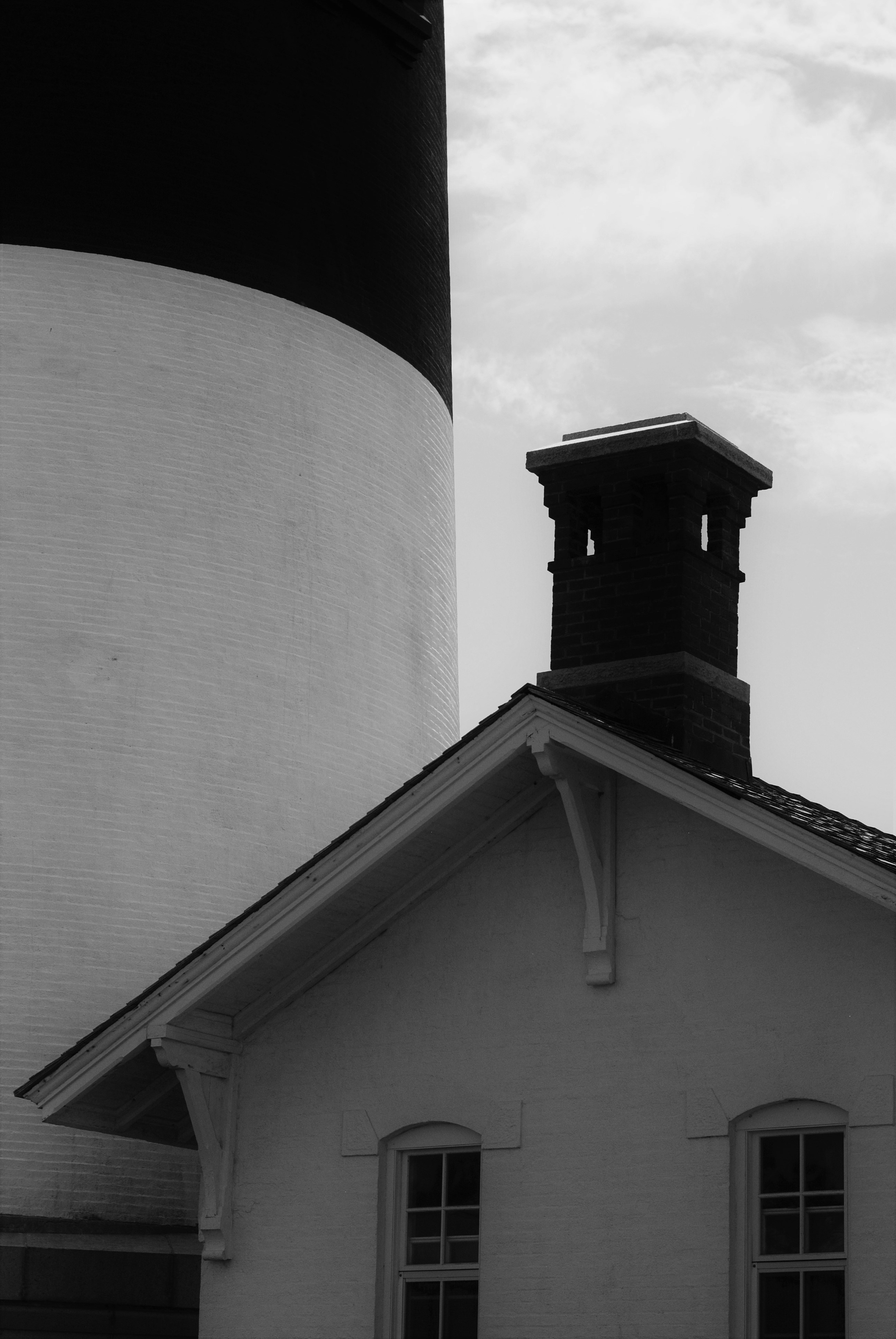 Brick Chimney Rising Over a Curved Lighthouse: A Quiet Architectural Moment