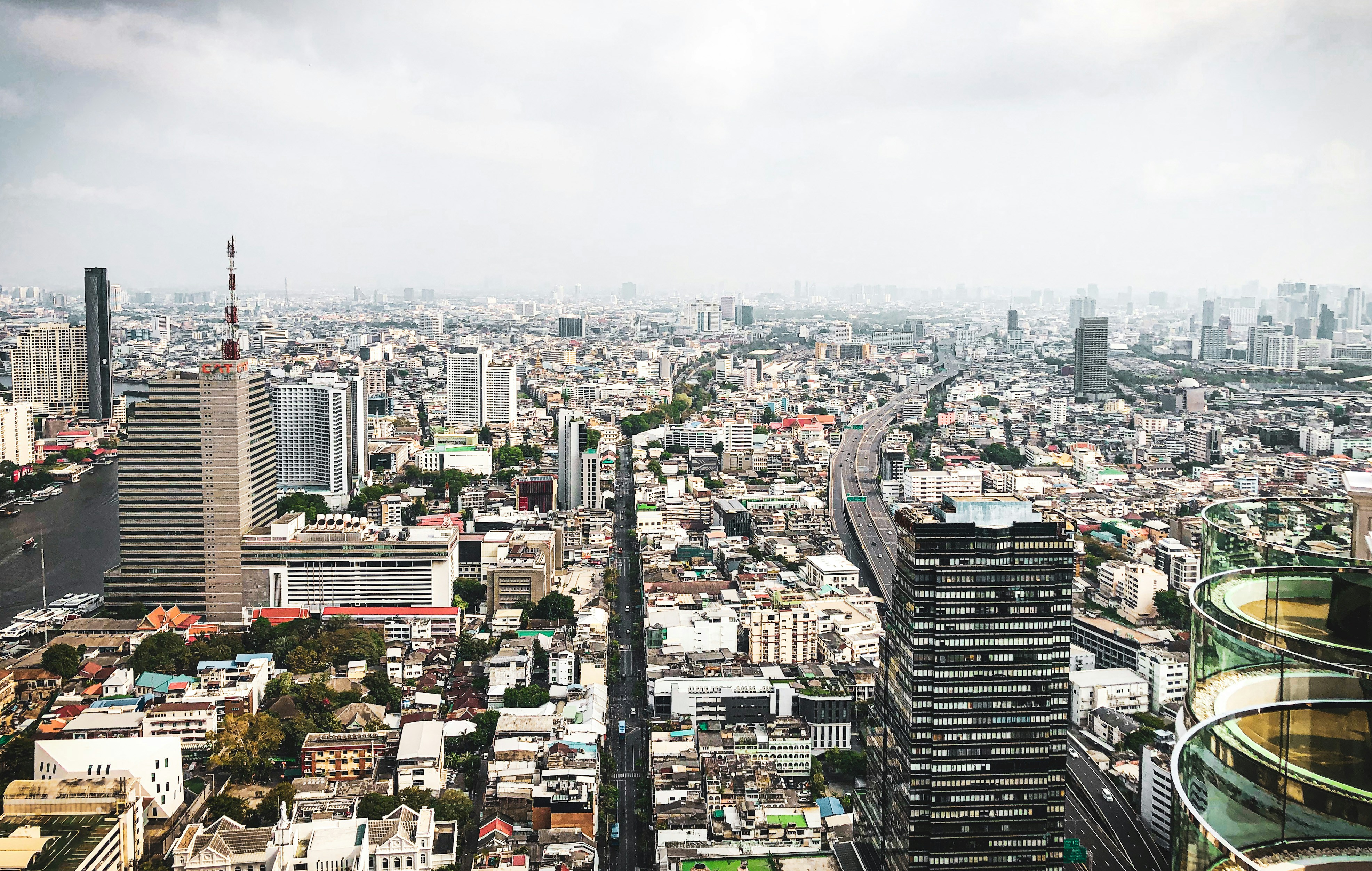 Expansive cityscape with high-rise buildings and a winding river under overcast skies.