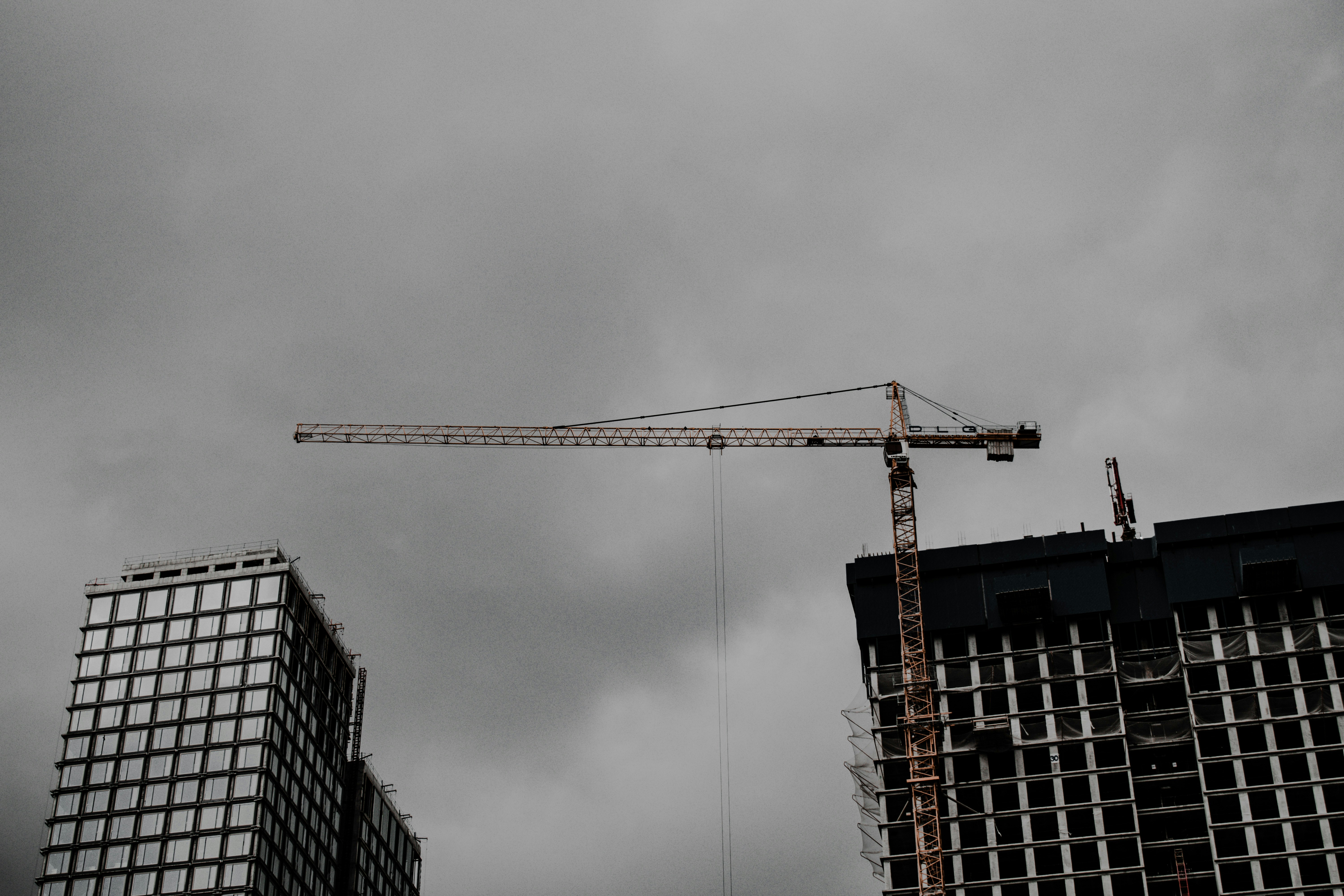 Construction crane towering over modern buildings under an overcast sky.