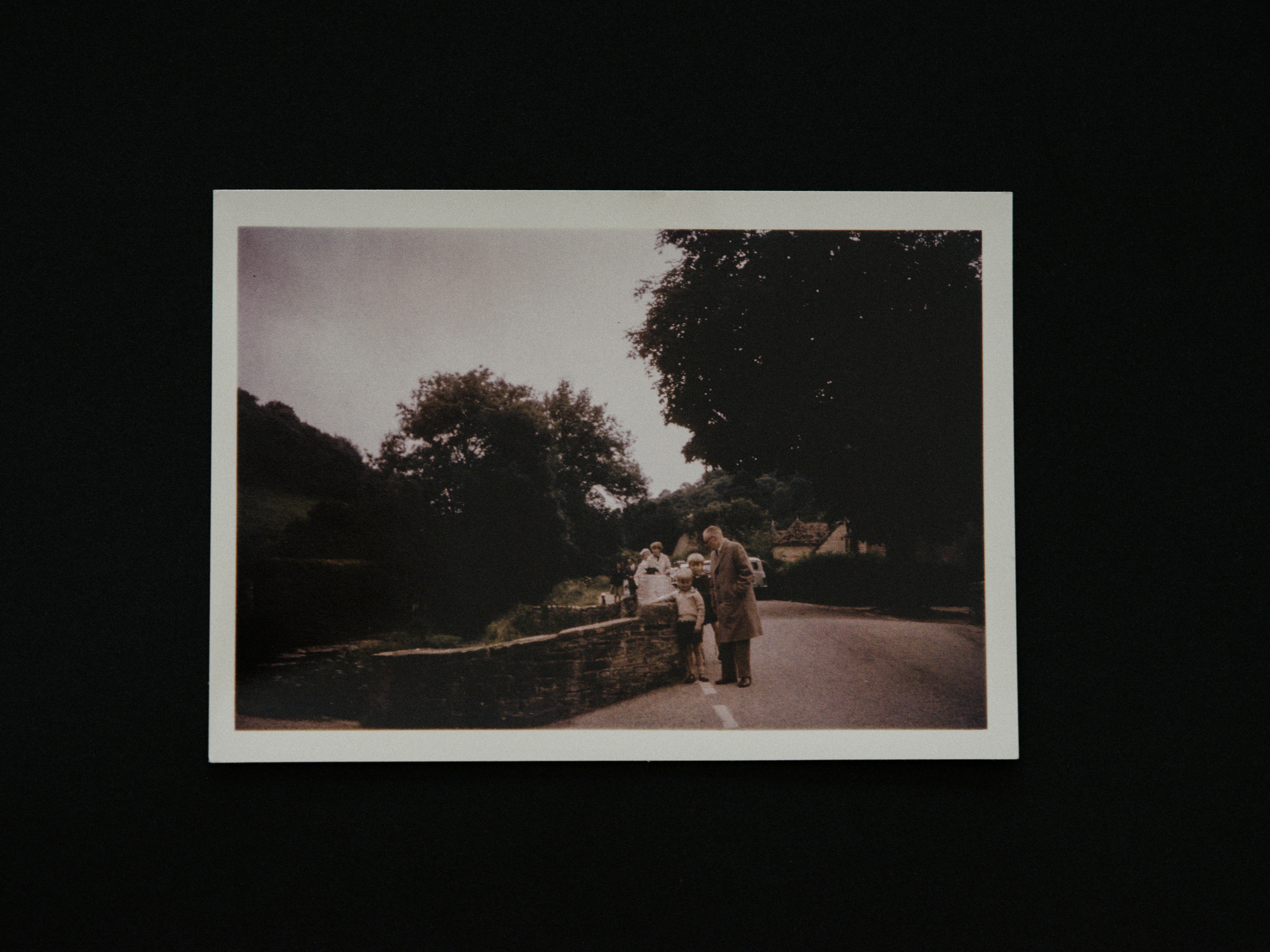 Vintage photograph of people gathered by a stone wall under overcast skies.
