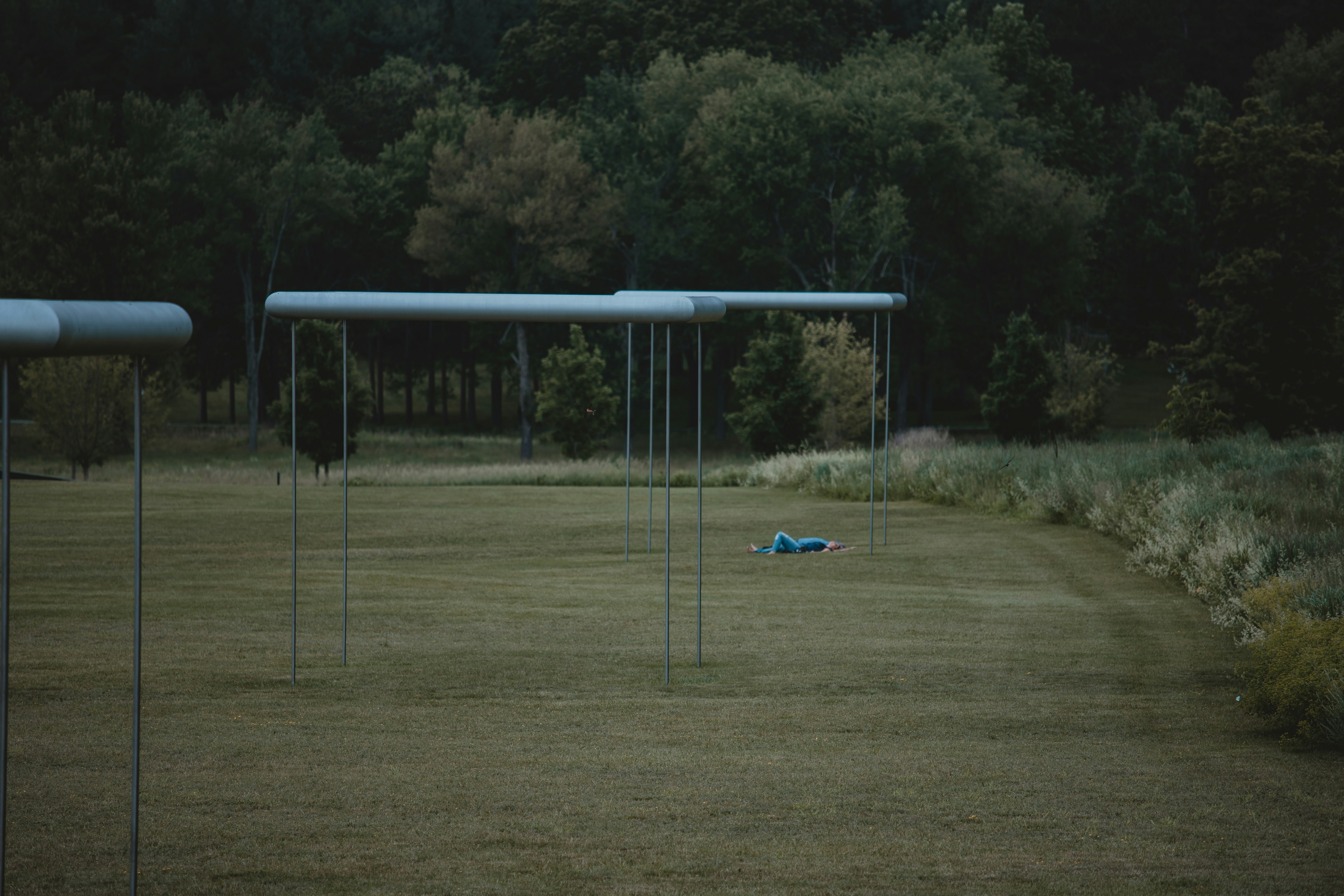 Blue-Clad Figure Resting Under Park Arches at Dusk