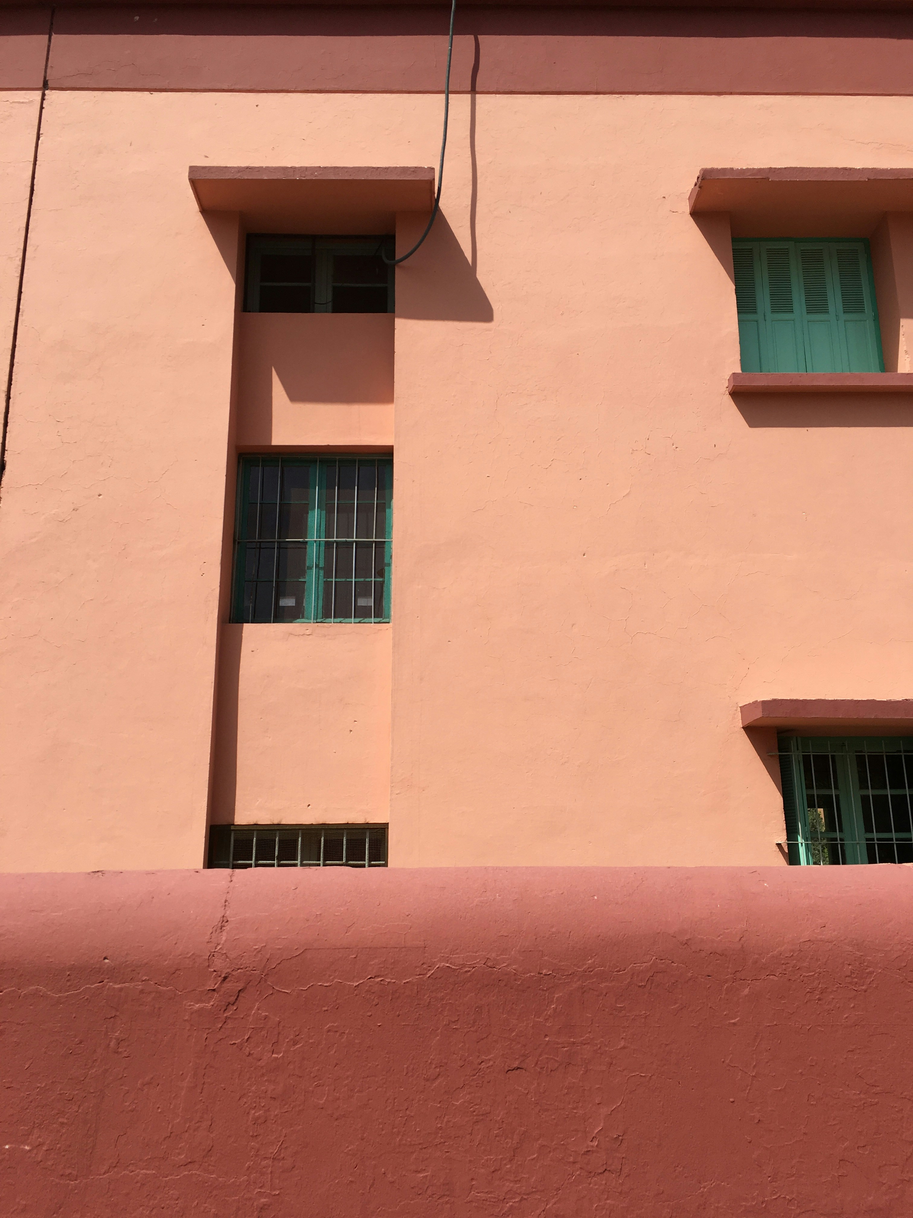 Sunlit Peach Facade: Emerald Shutters and a Vertical Window Stack