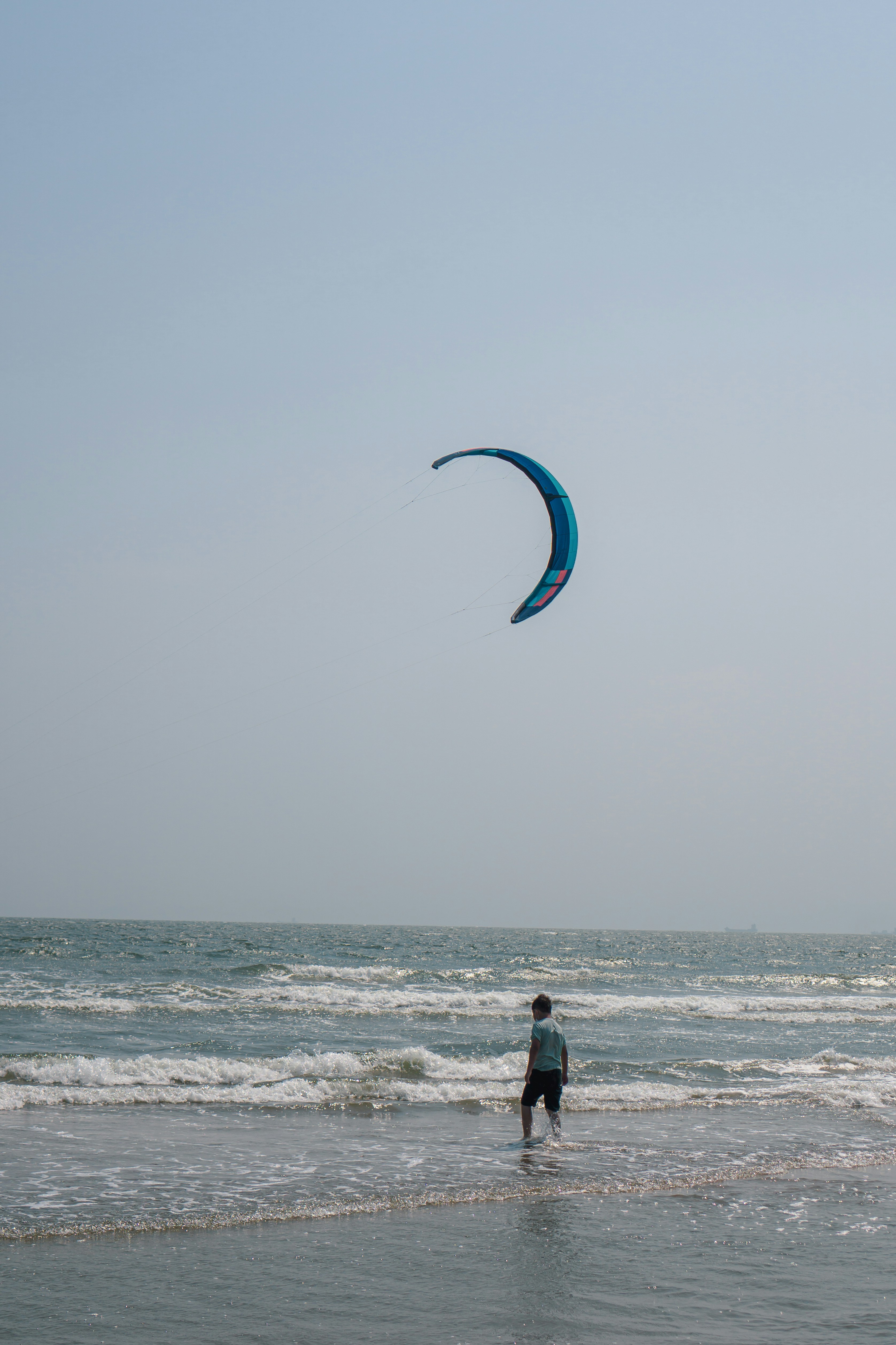 Blue Arc Over Quiet Seas: A Lone Figure at the Shore