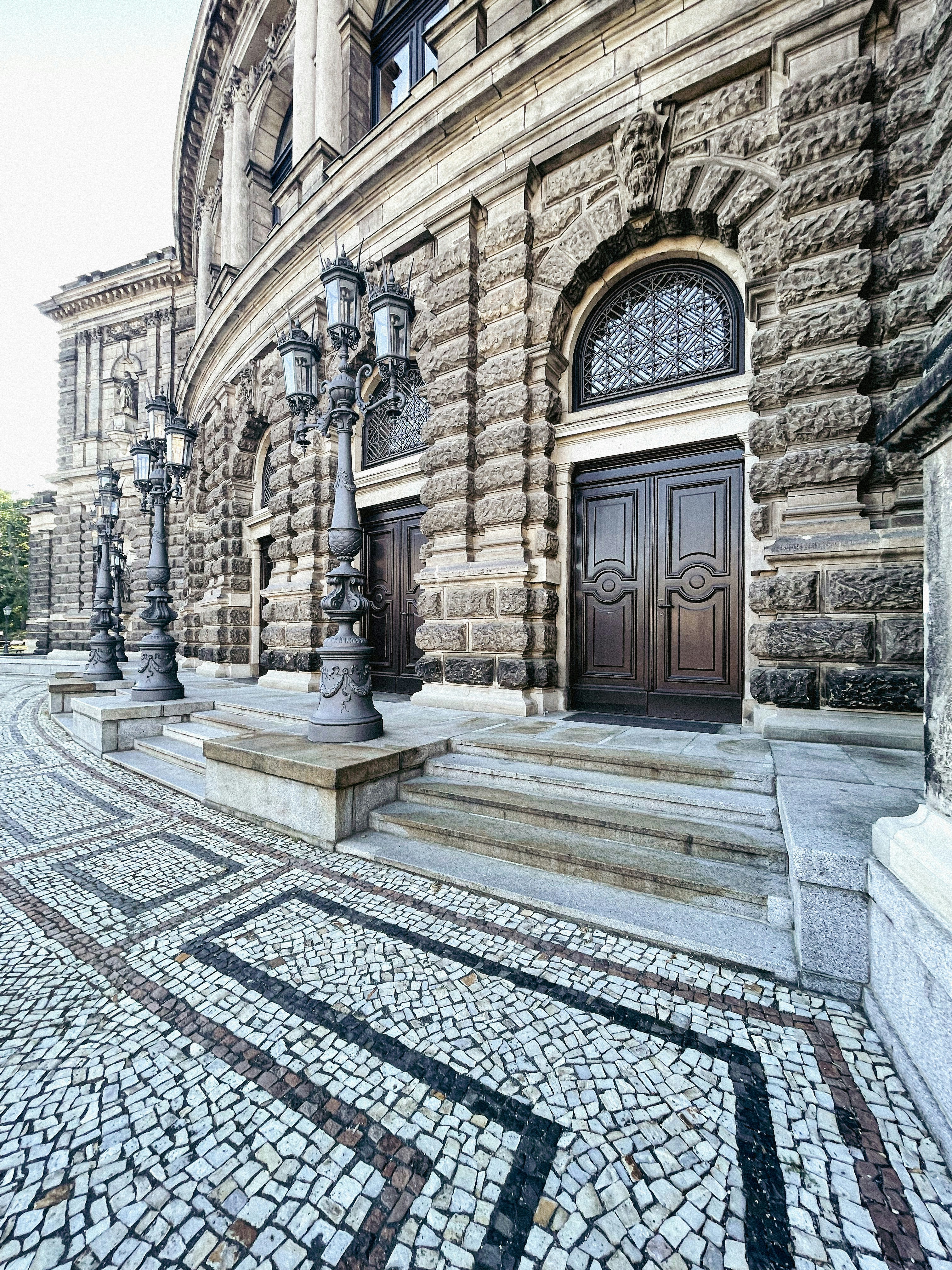 Lanterns Guard the Curved Facade: Timeworn Stonework Meets Mosaic Streets