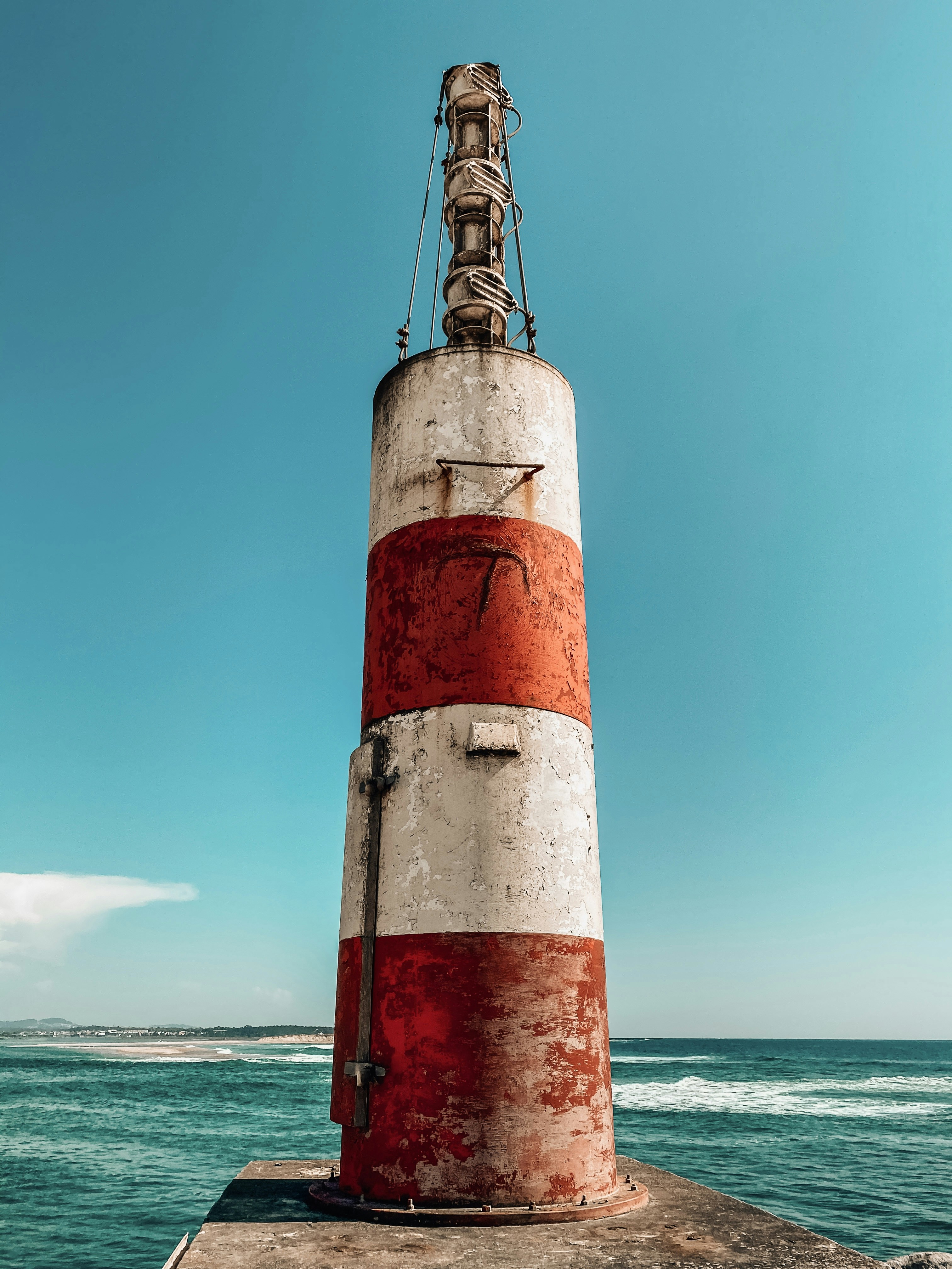 Red and white striped lighthouse on the beach during daytime photo ...