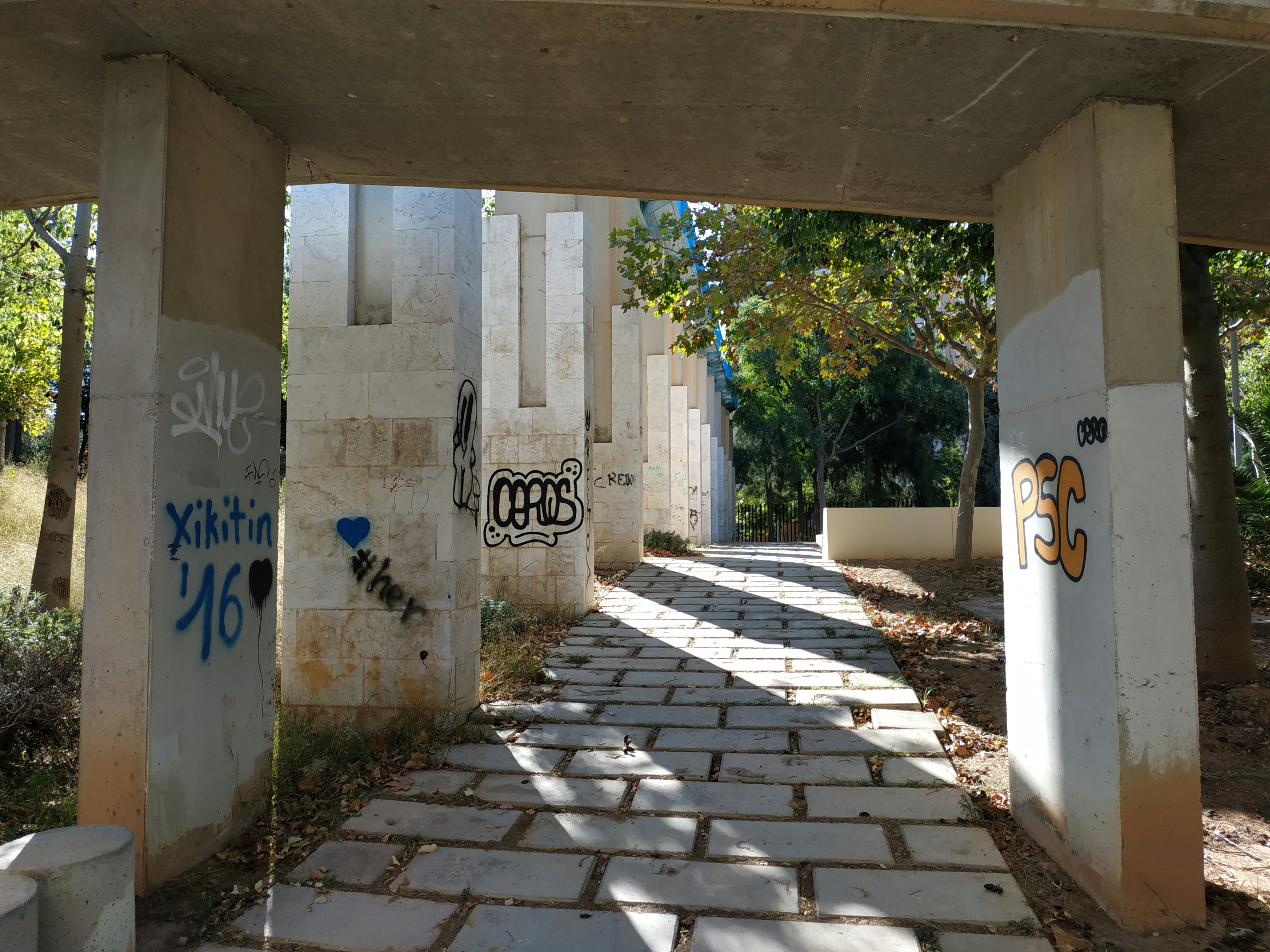 Shadowed Arcade: Sunlit Path Through Graffiti-Colonnade