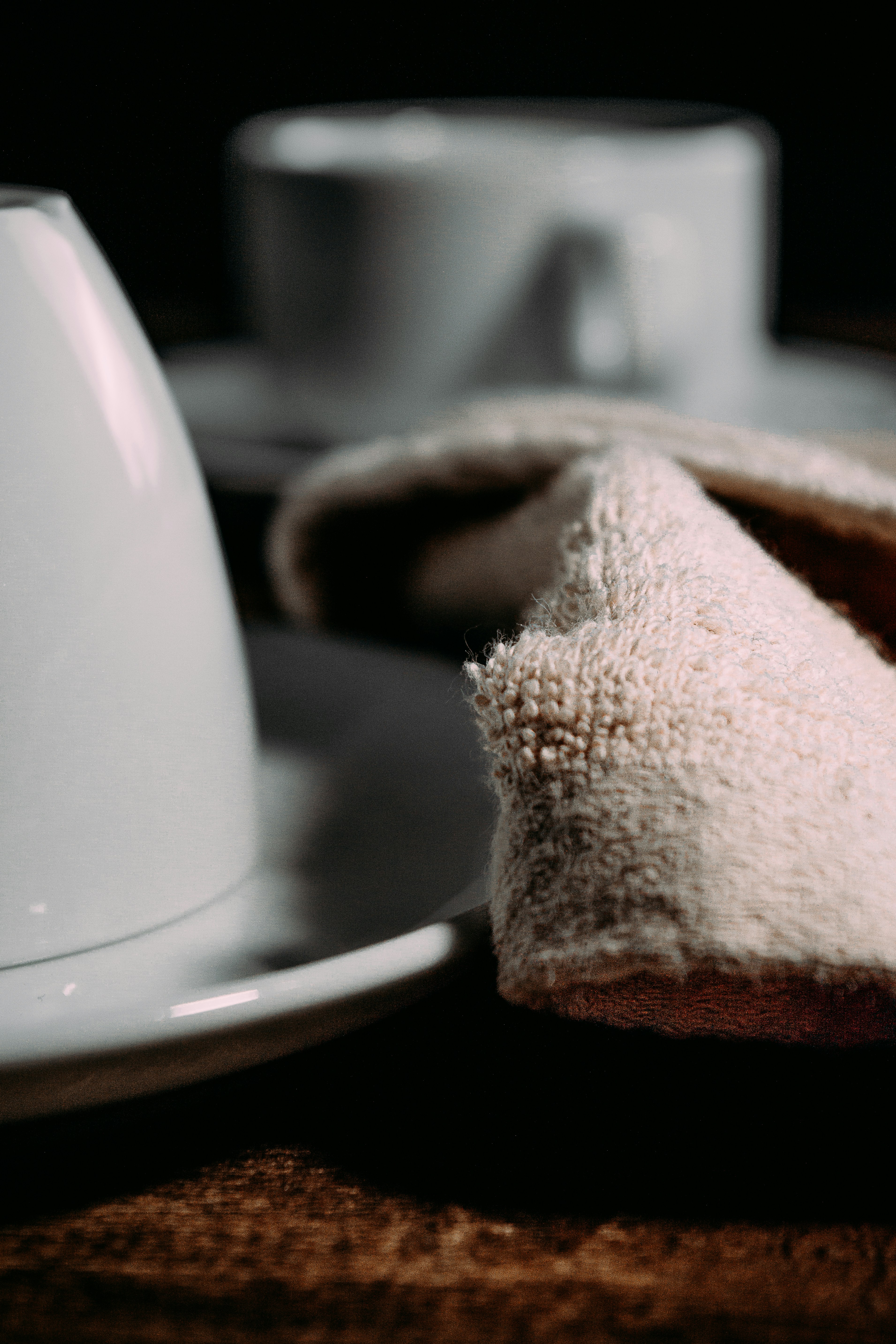 Texture in Focus: A Beige Towel Framed by a White Teacup in Low-Key Light