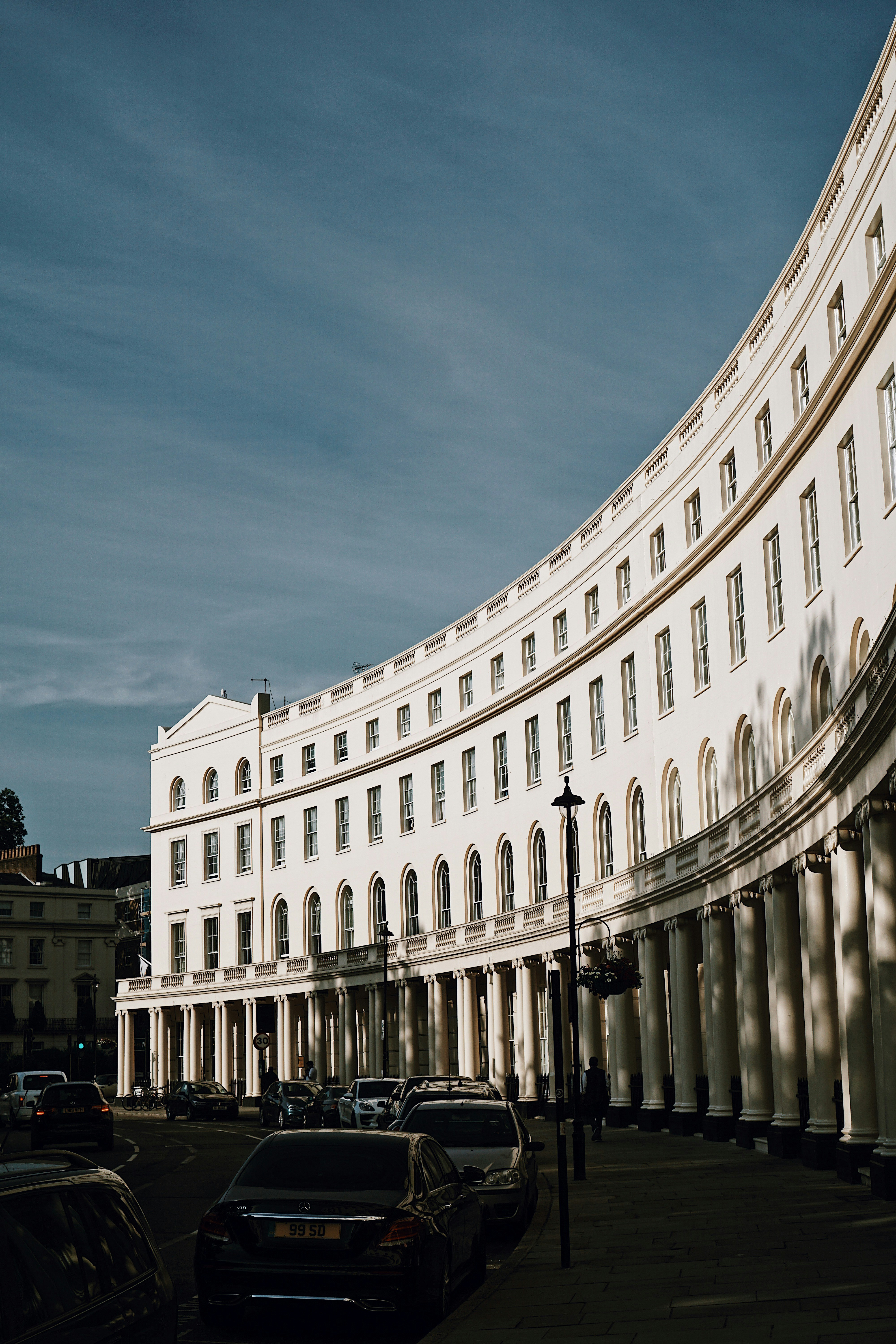 A grand curved building with classical architecture, showcasing its elegant columns and detailed windows under a clear blue sky.