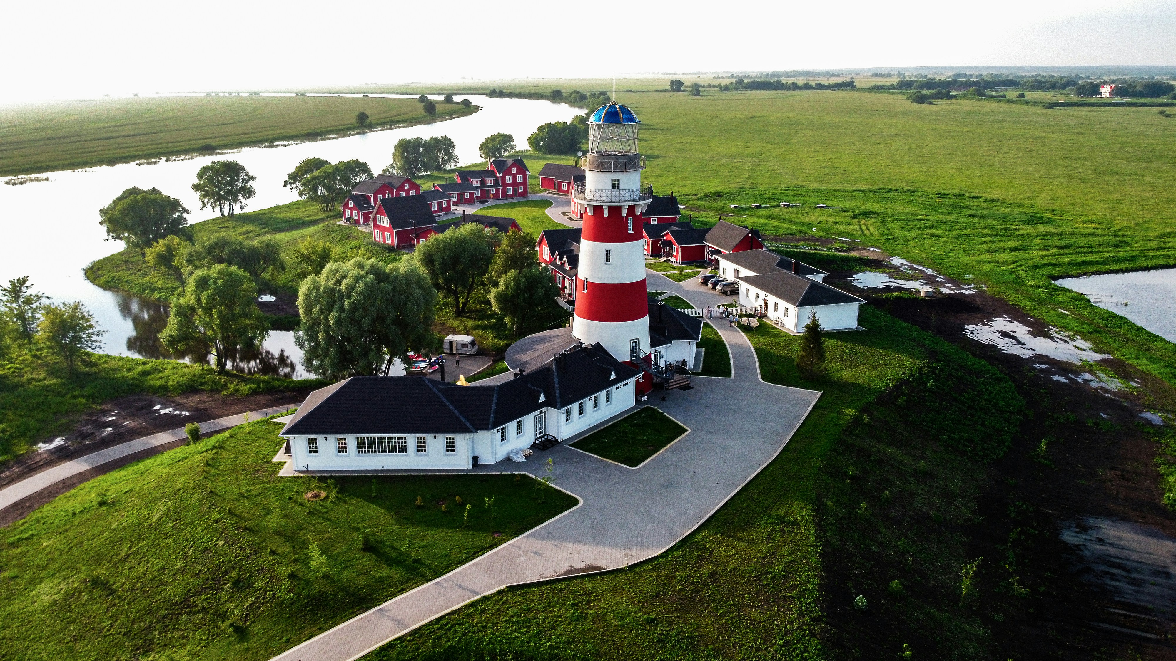 Striped Lighthouse Over a Curved Drive Through Emerald Fields