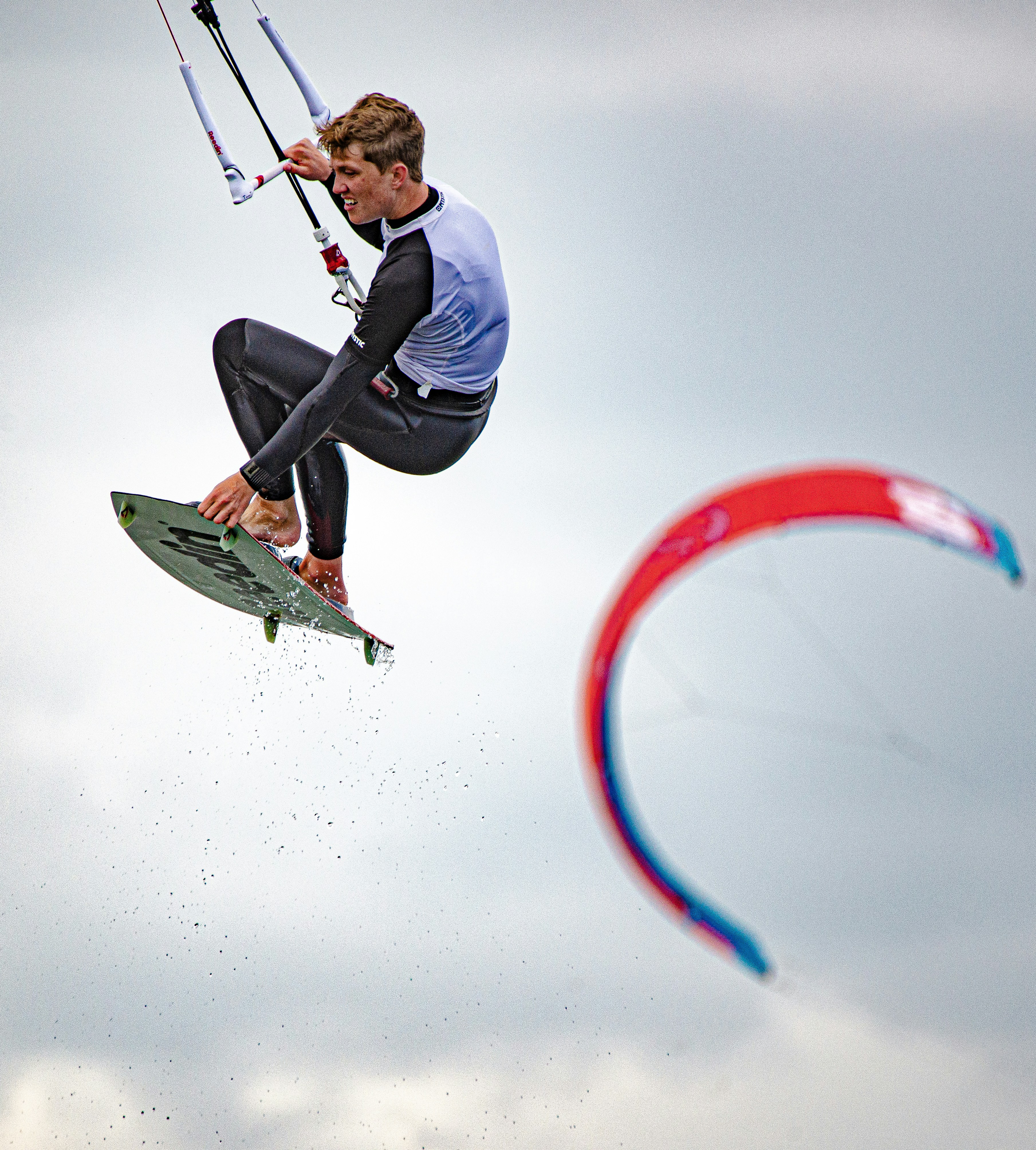 Aerial Maneuver: Windsurfing Kiteboarder mid‑Jump Against a Clouded Sky