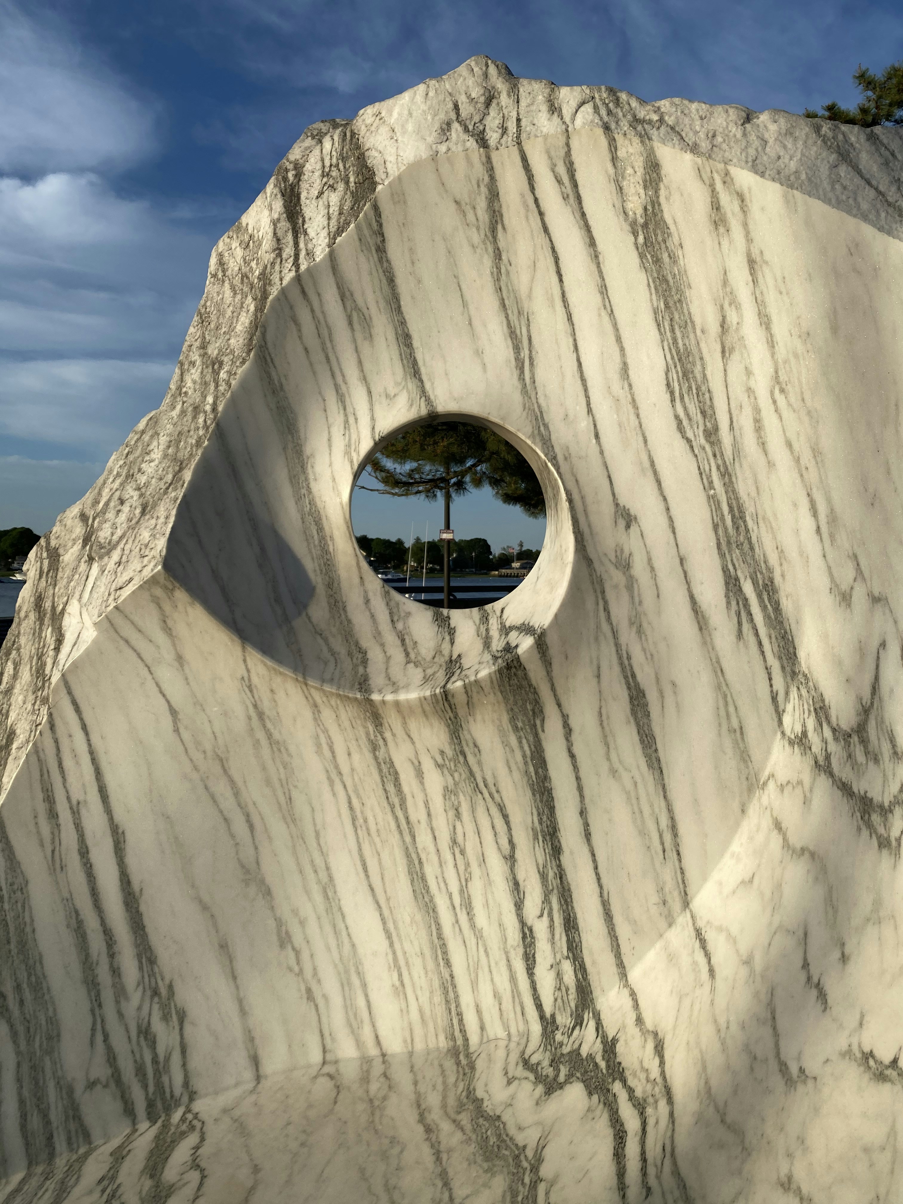 Circular Portal in Marble Monolith: A Sunlit Grotto Framed by Veined Stone