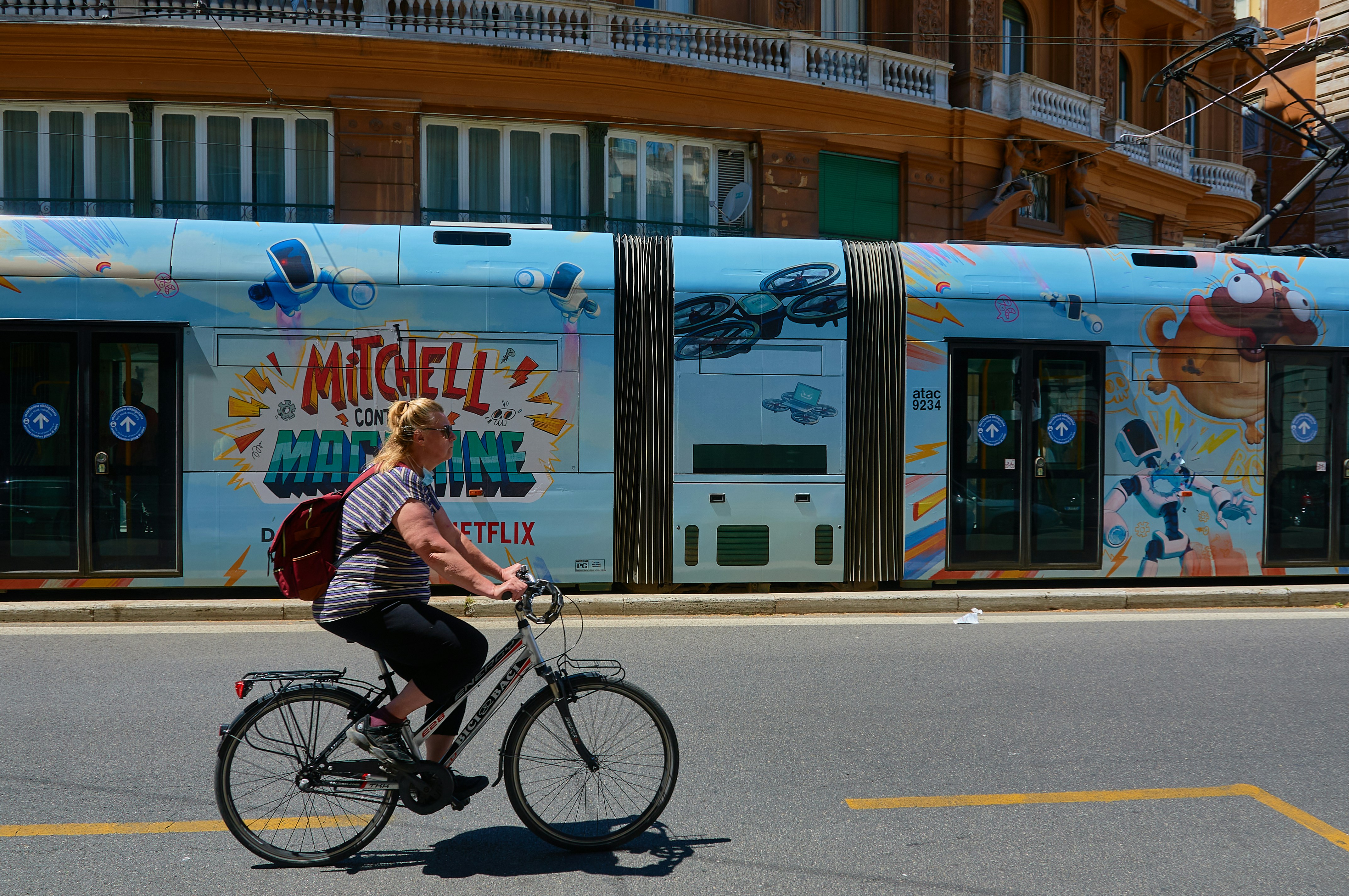 Cyclist in Striped Tee Rides Past a Bright Transit Mural