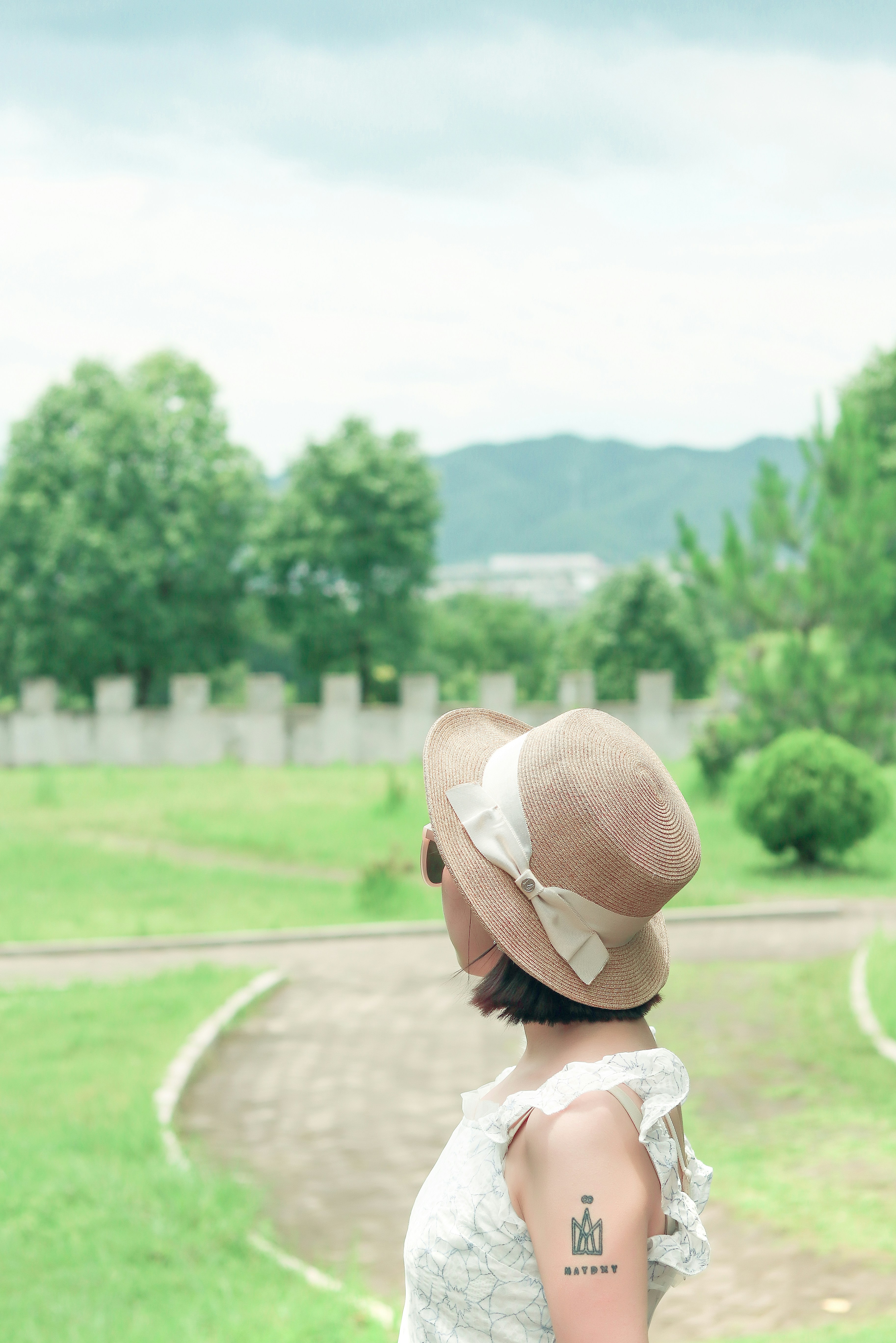 Soft-Focus Portrait in a Sunlit Park: Hat, Lace Dress, and a Tattoo