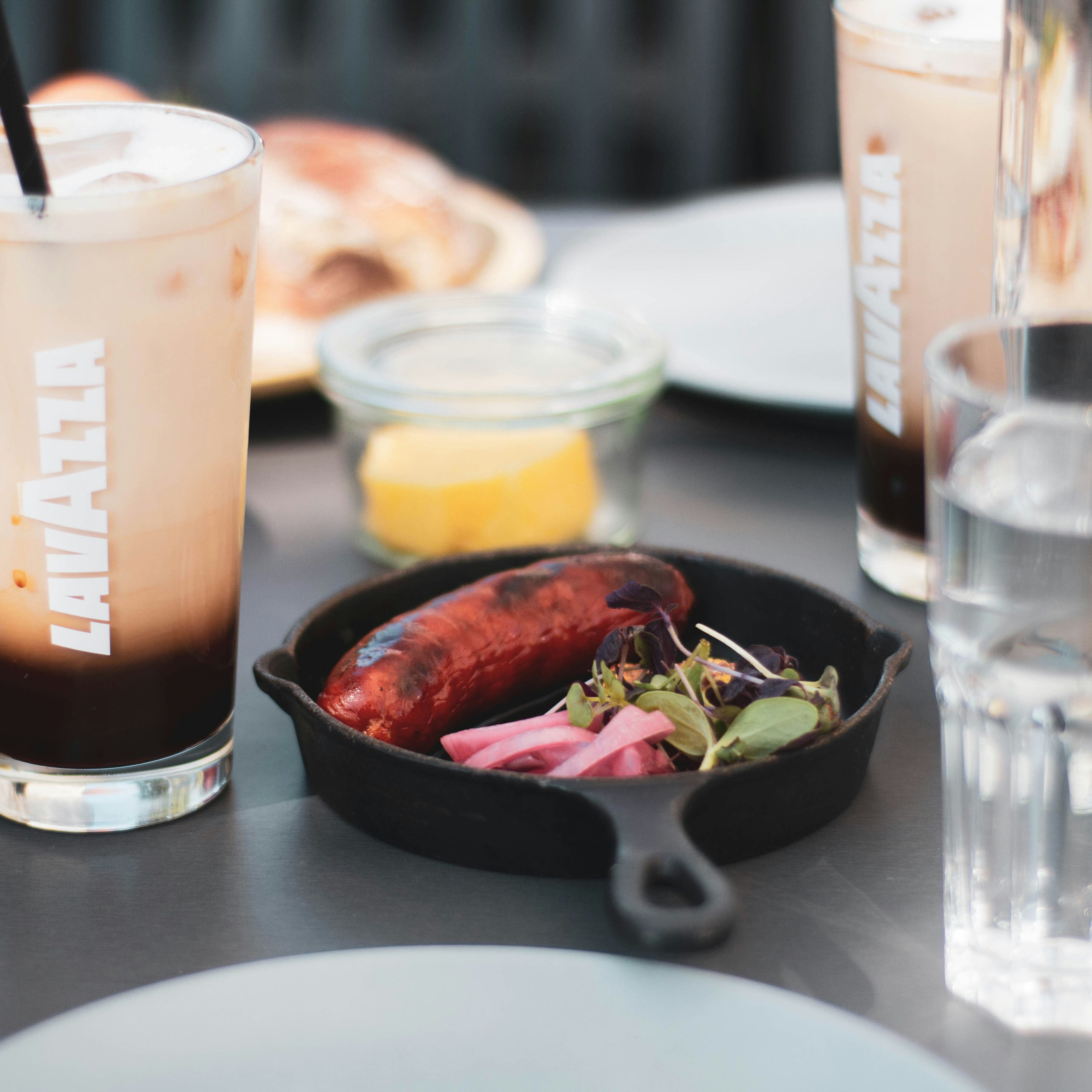 Sizzle and Sip: Cast-Iron Sausage on a Sunlit Patio with Iced Coffee