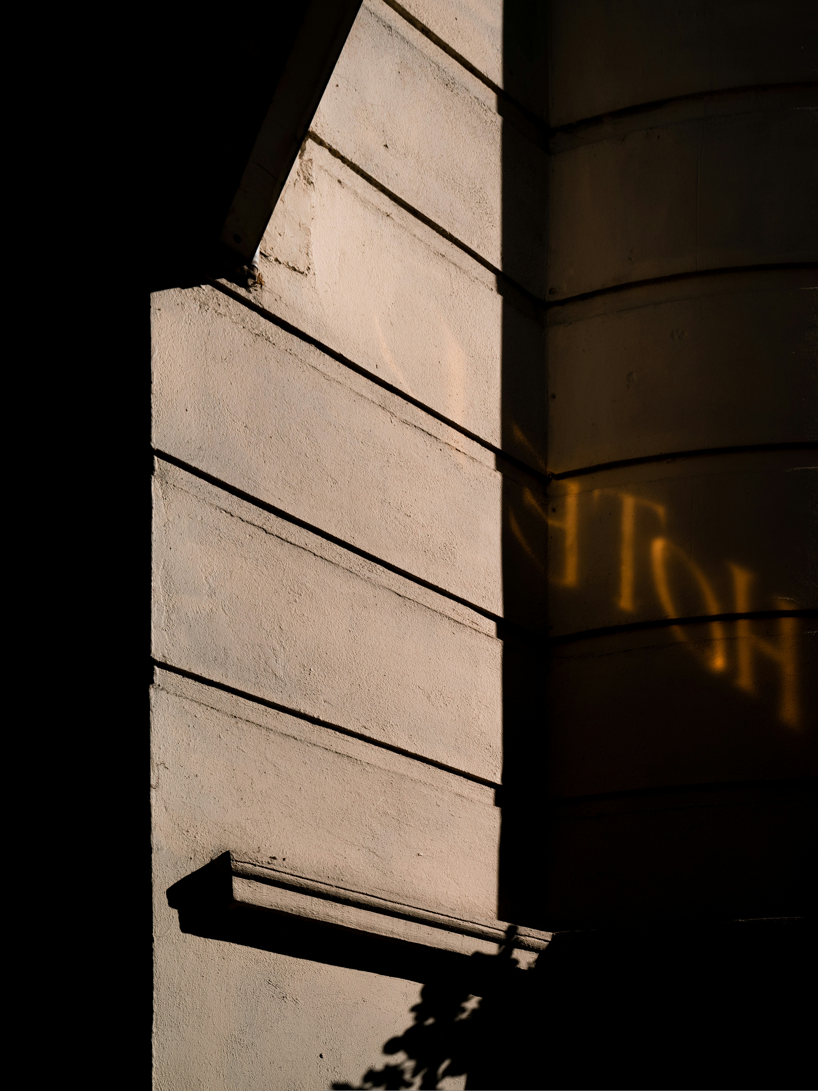 Subtle interplay of light and shadow on a textured wall, revealing the word 'STOP' in a unique projection.