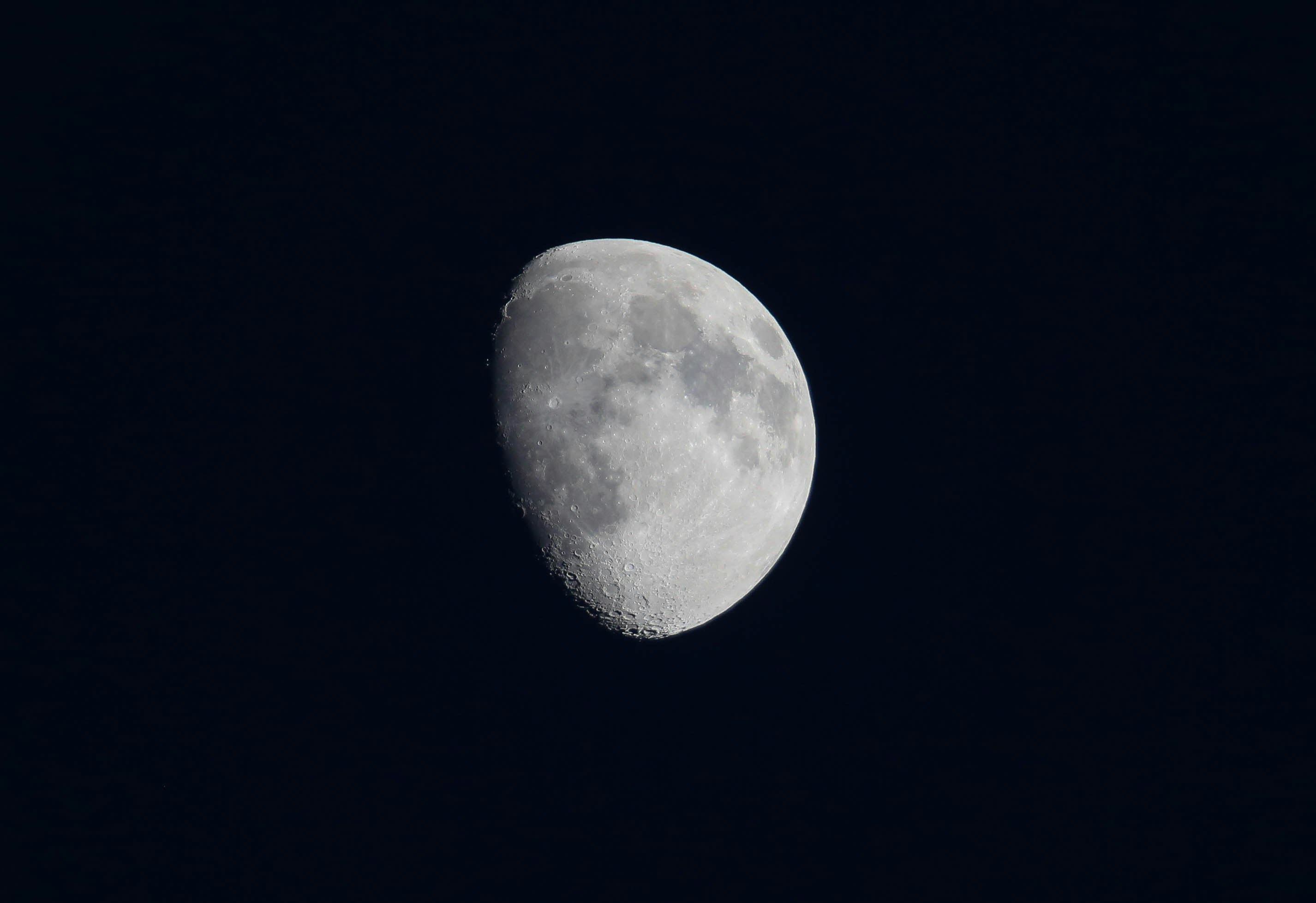 Waxing crescent moon illuminated against a dark sky, showcasing detailed craters and textures.