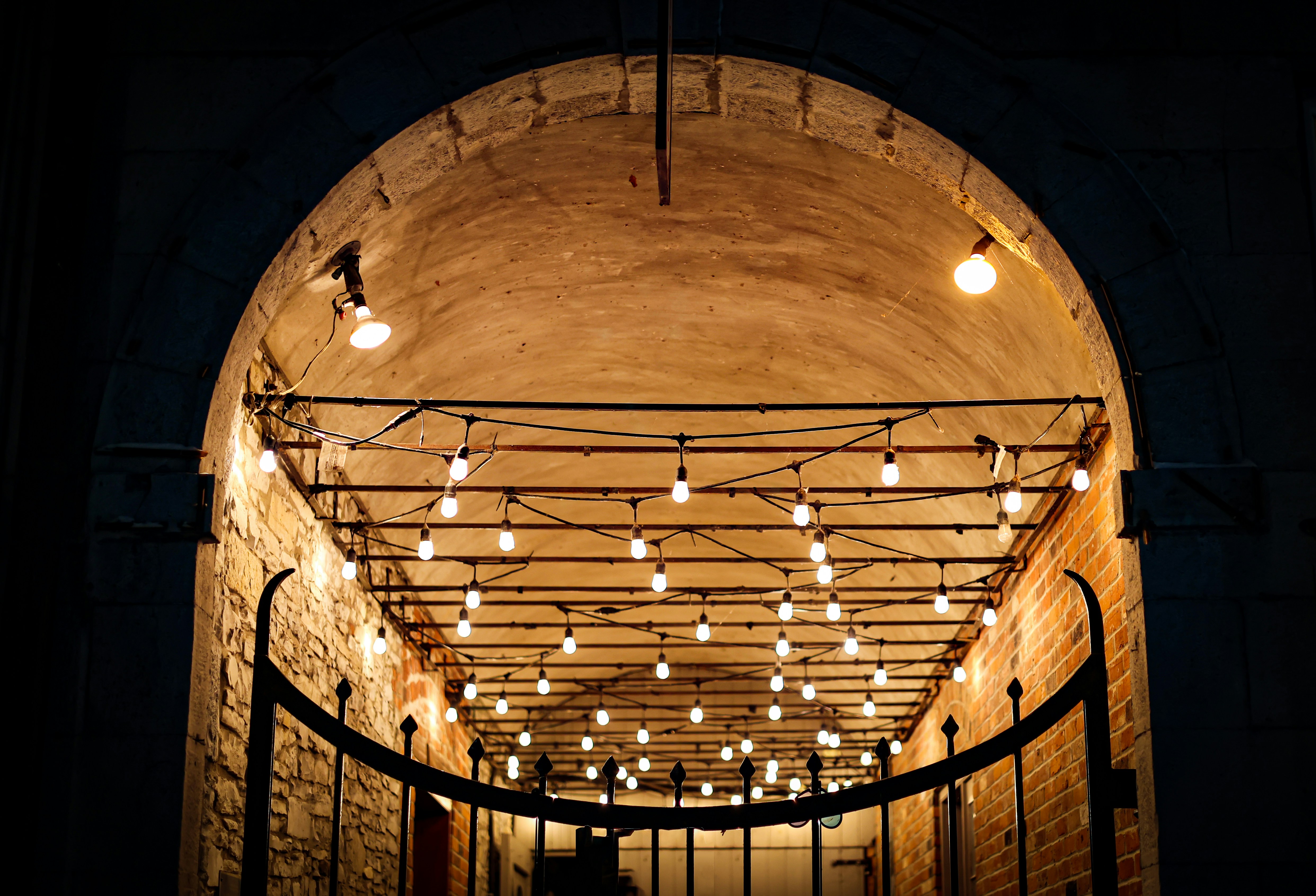 Warm glow of string lights through a brick archway