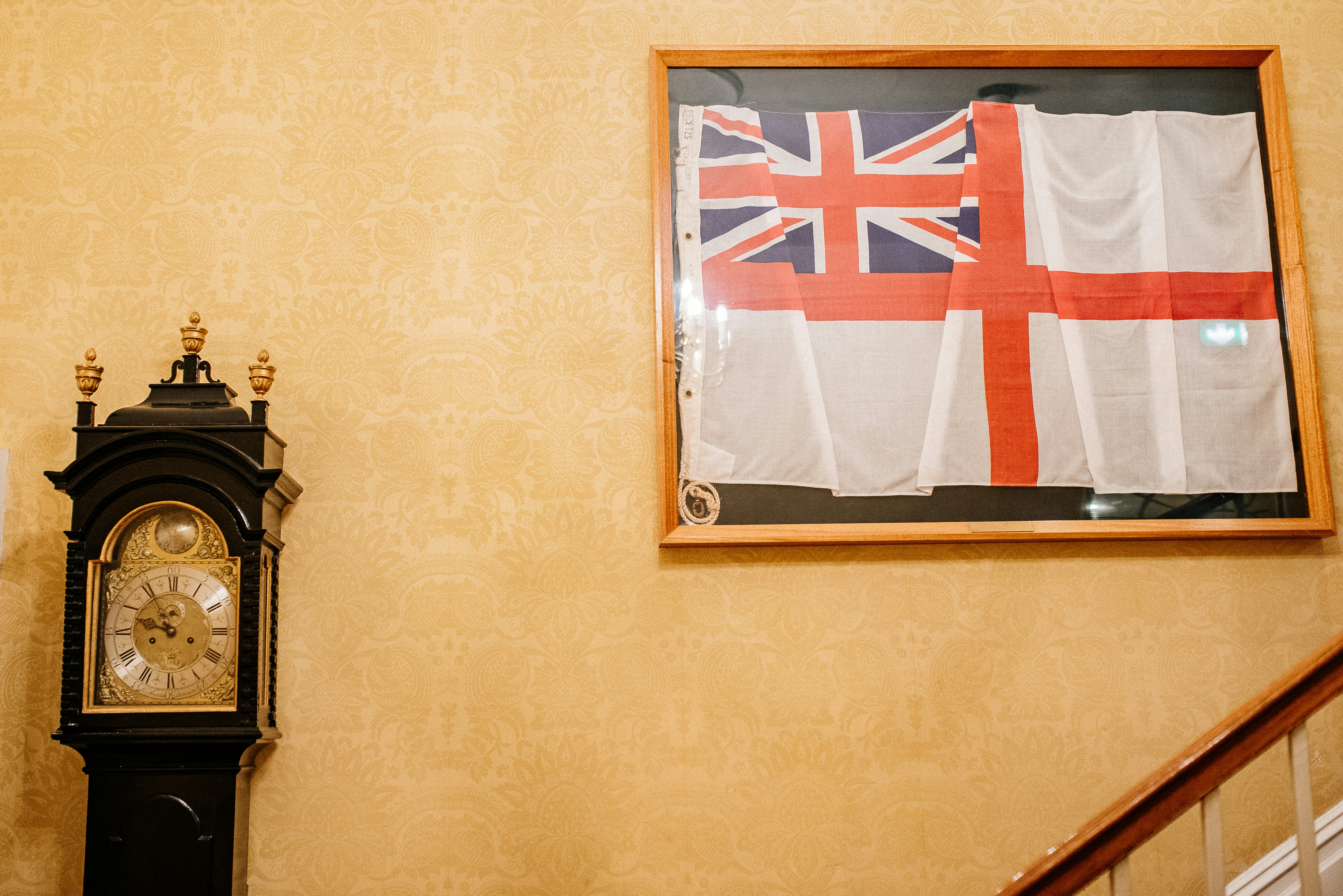 Ticking Heritage in Warm Light: A Vintage Clock Framed by a Flag
