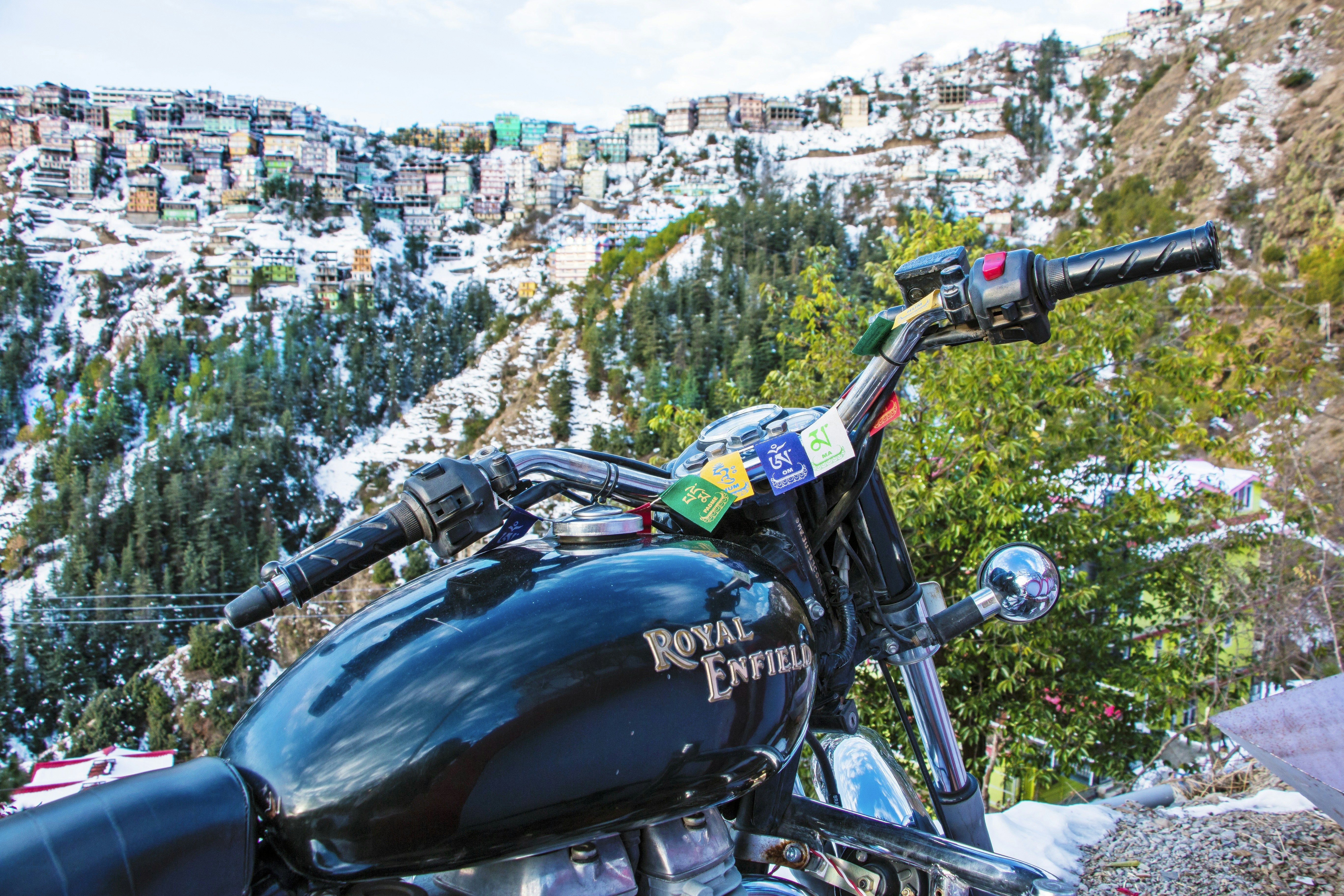 Blue and black motorcycle on snow-covered terrain with mountain backdrop.