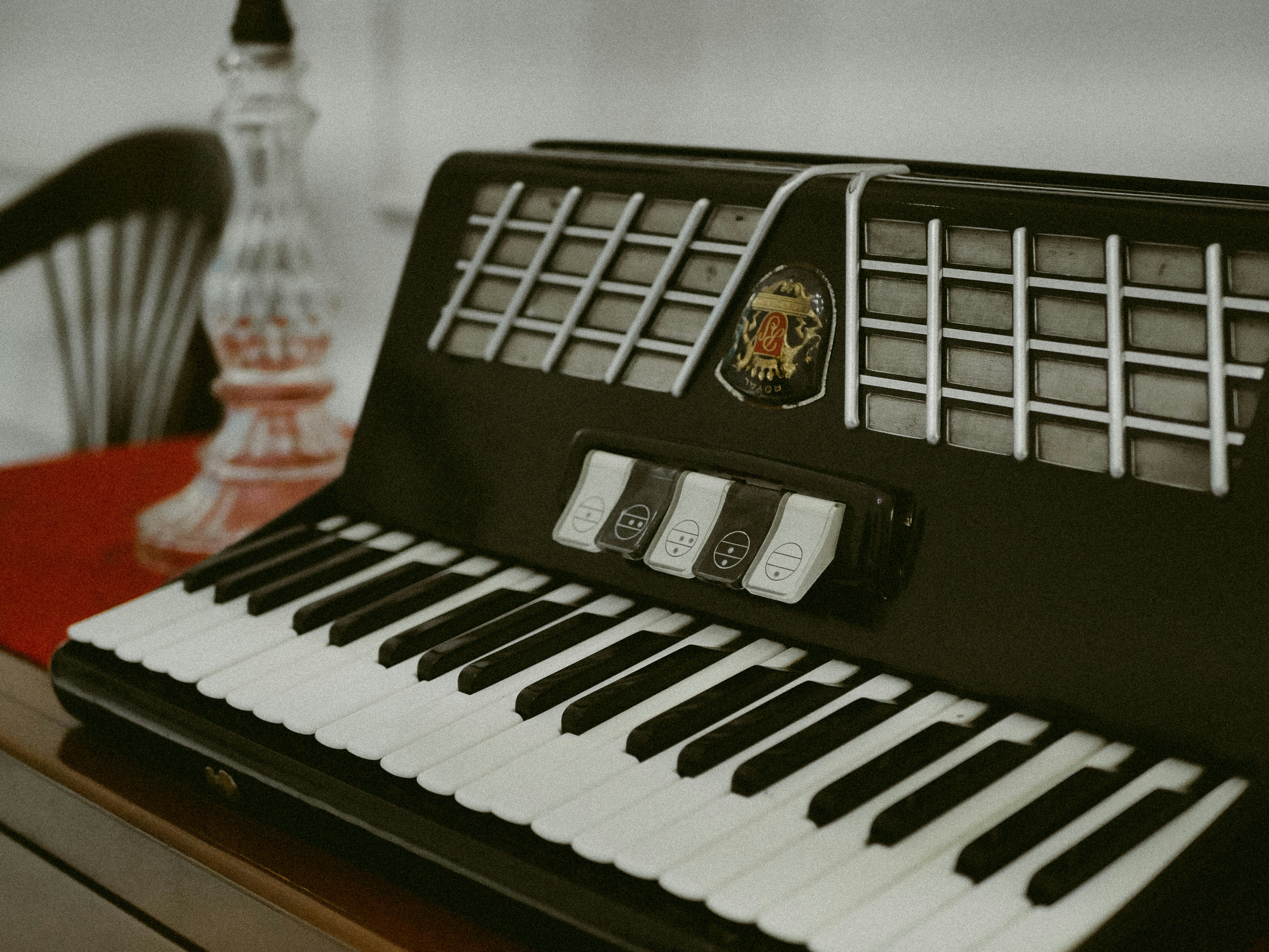 Vintage accordion with black and white keys resting on a polished surface, accompanied by a decorative glass lamp in the background.