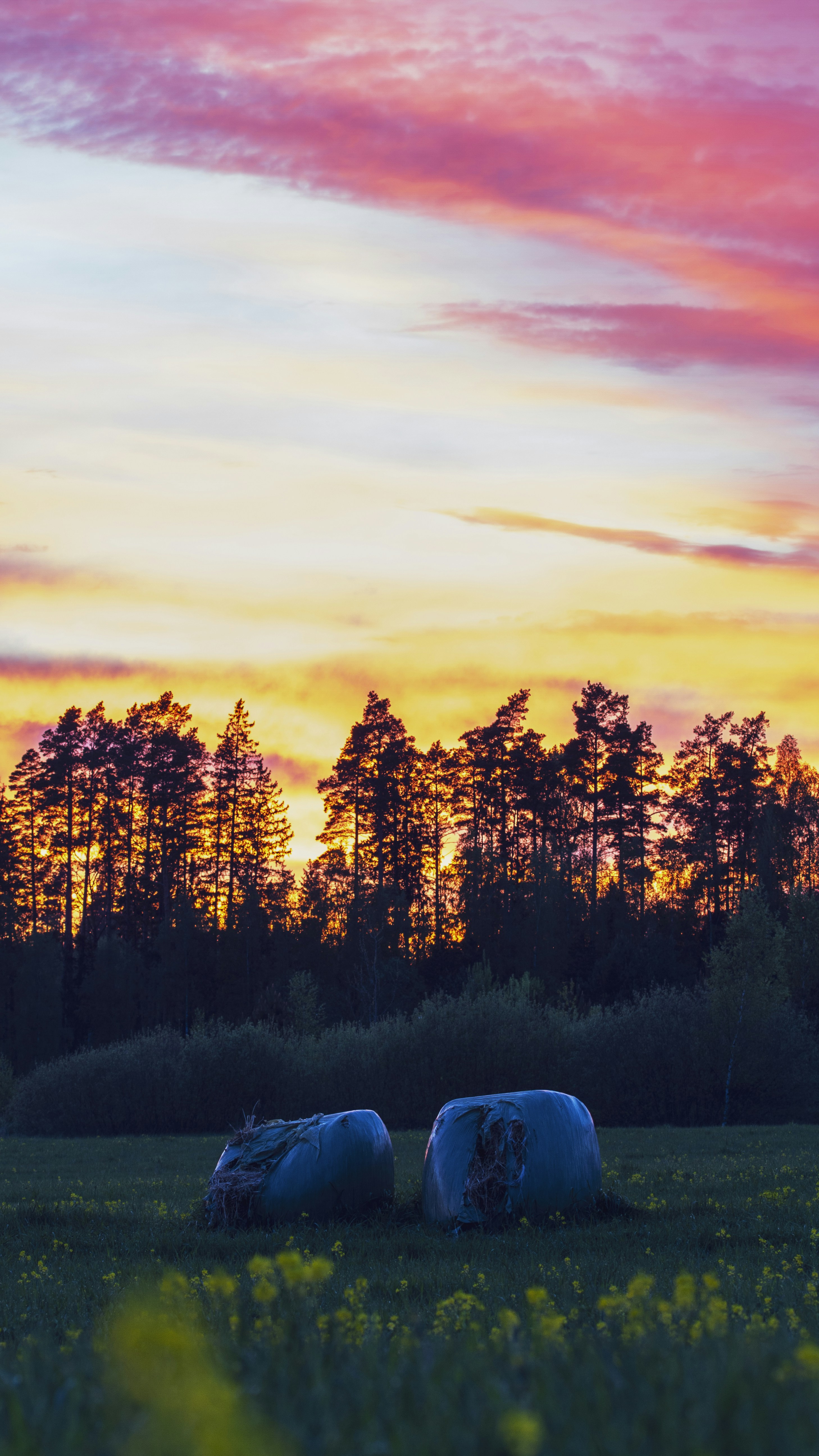 Dusk Hay Bales Under a Fiery Horizon