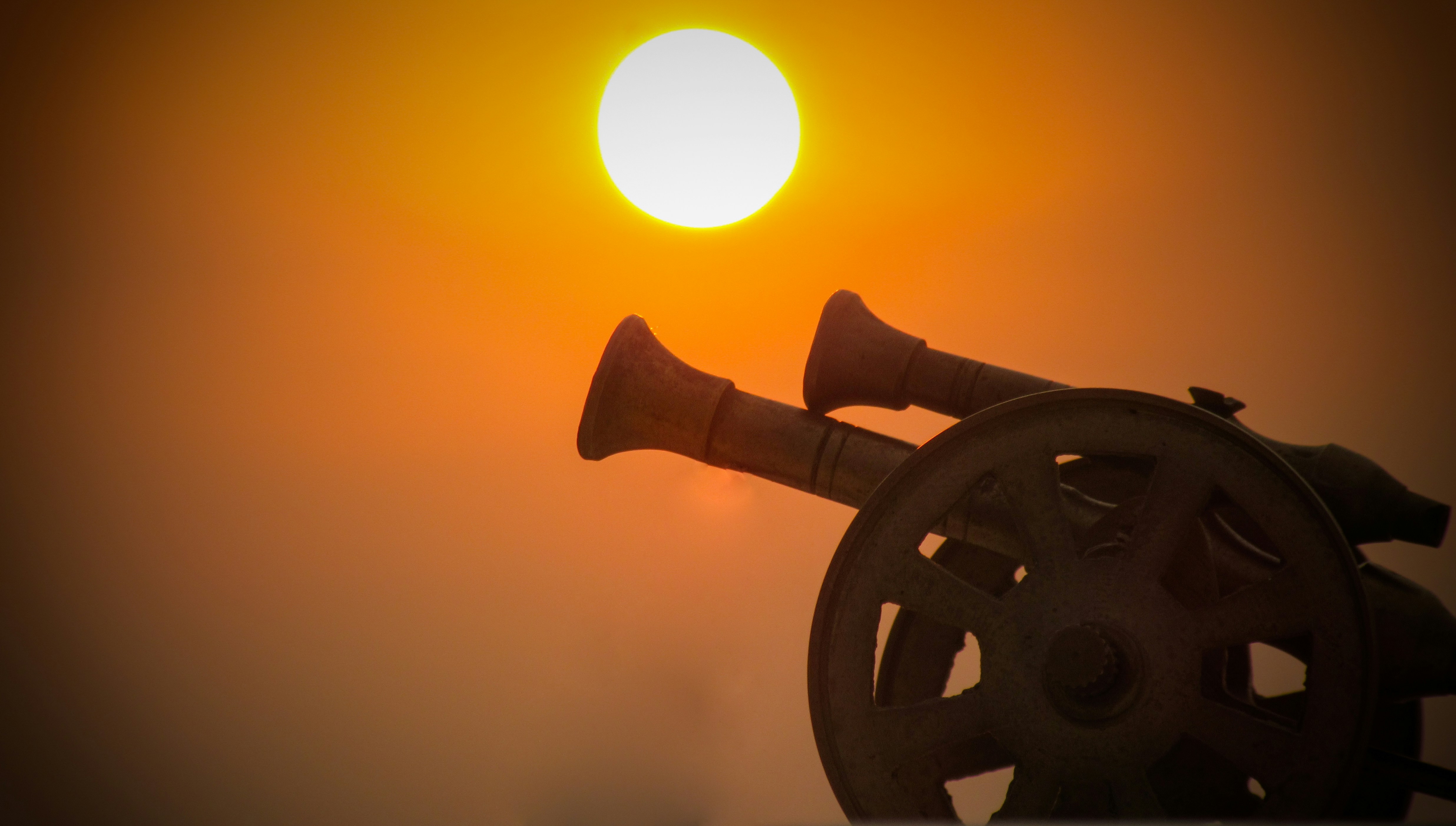 Orange Hour Silhouette: The Ship’s Cannon Wheel Against a Dusk Sun