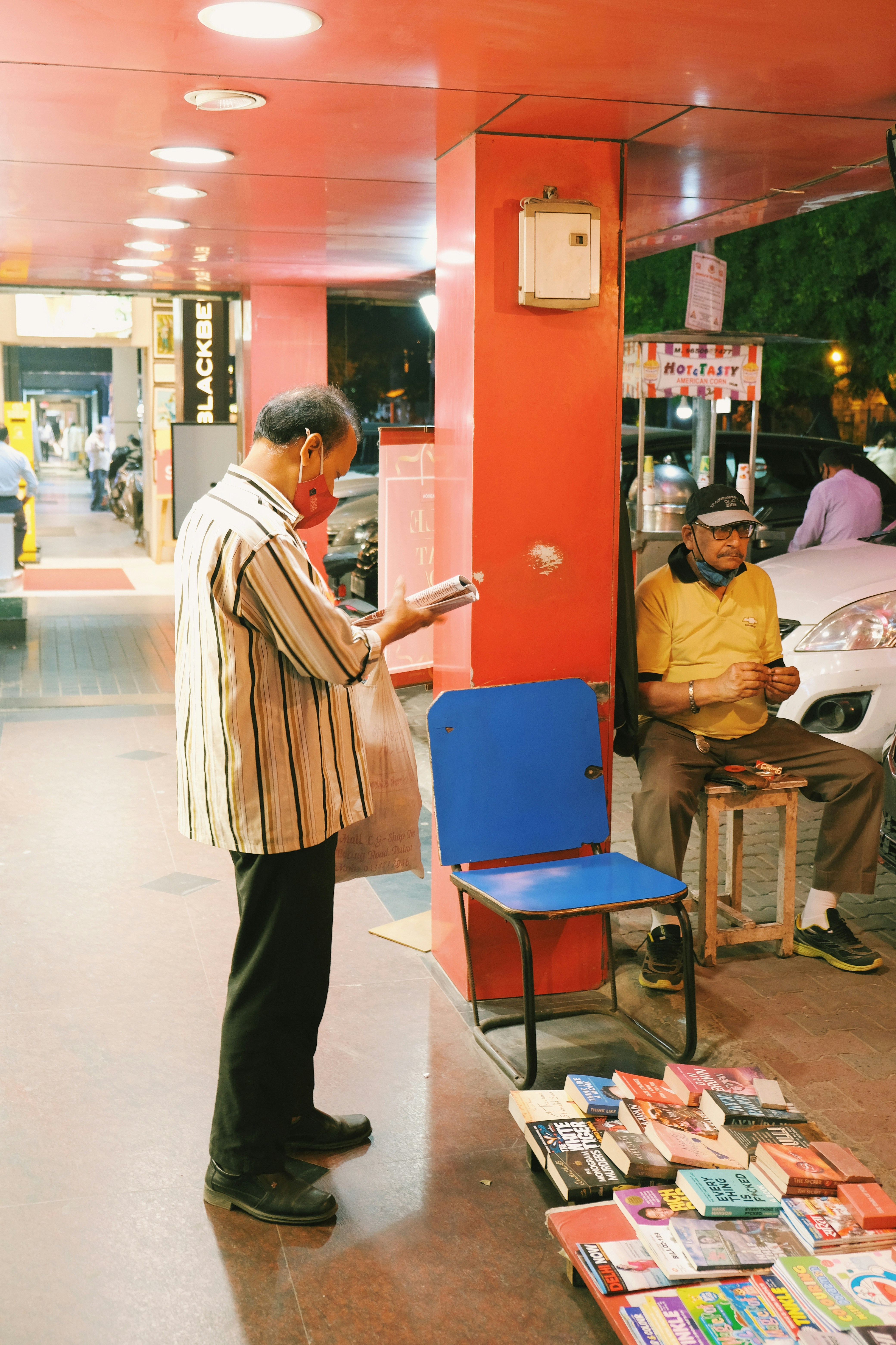 Under the Orange Canopy: A Reader Pauses at a Street Market