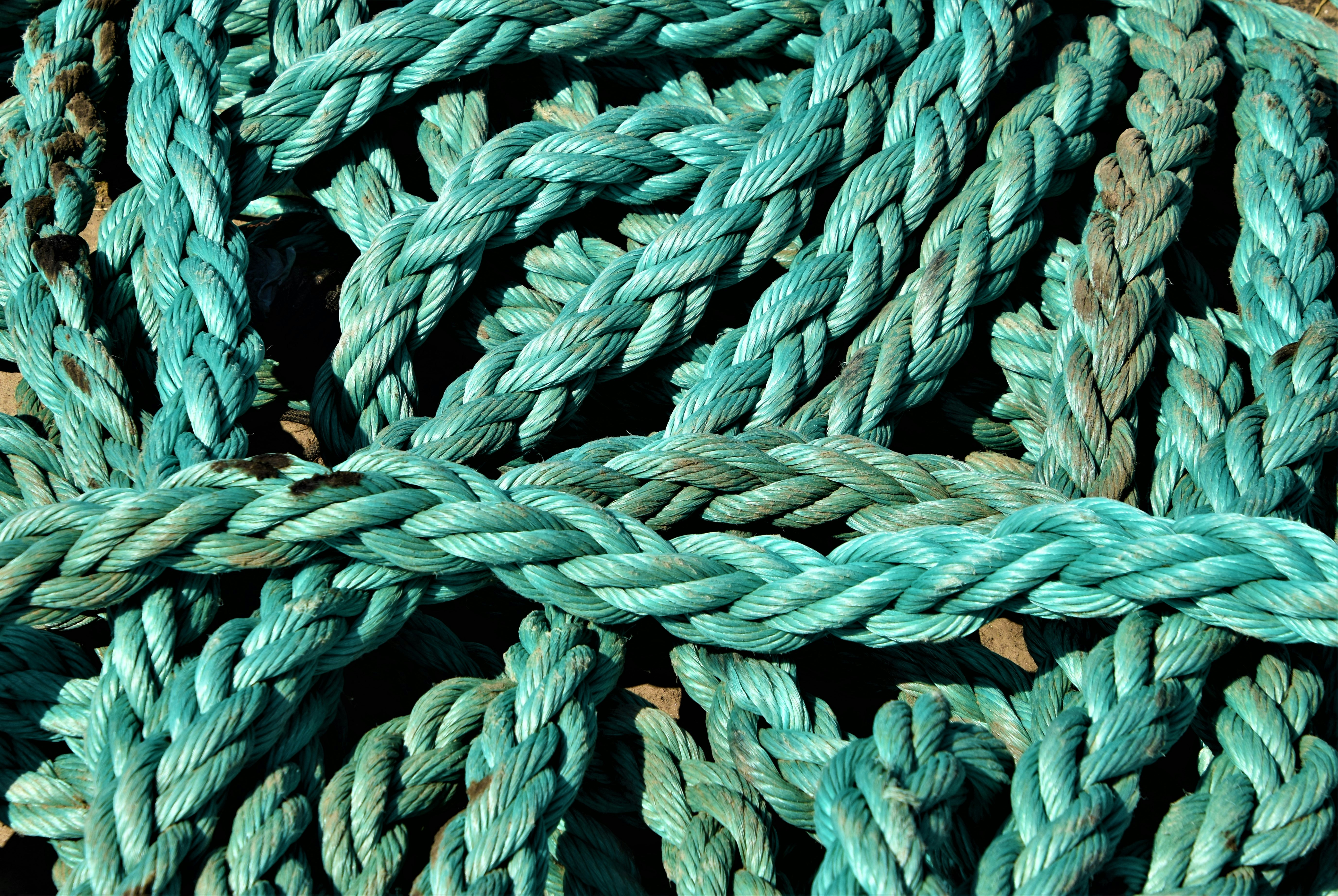Close-up of intertwined turquoise ropes showcasing the texture and patterns inherent in marine equipment.