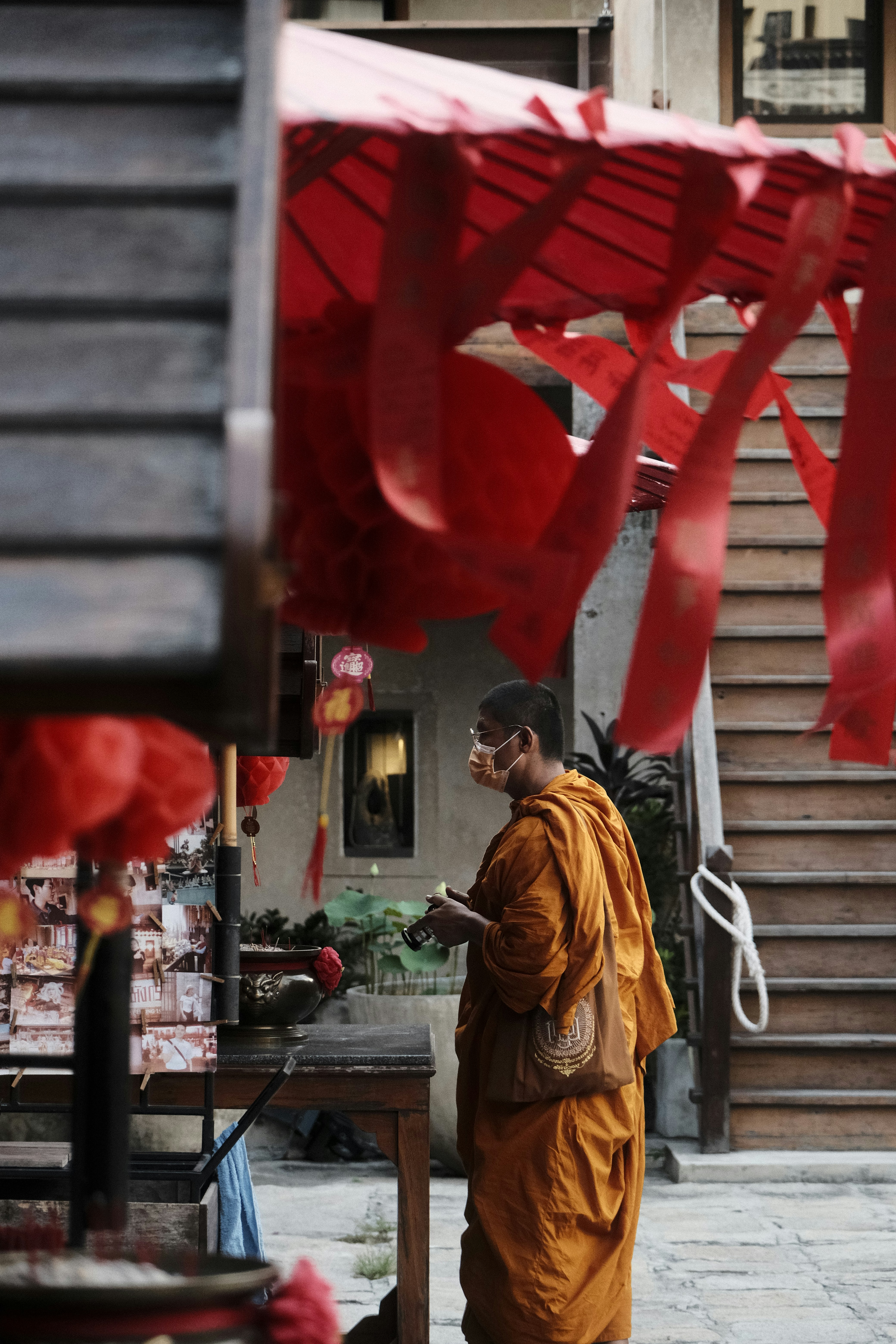 Monk in saffron amid red lanterns in a quiet temple courtyard