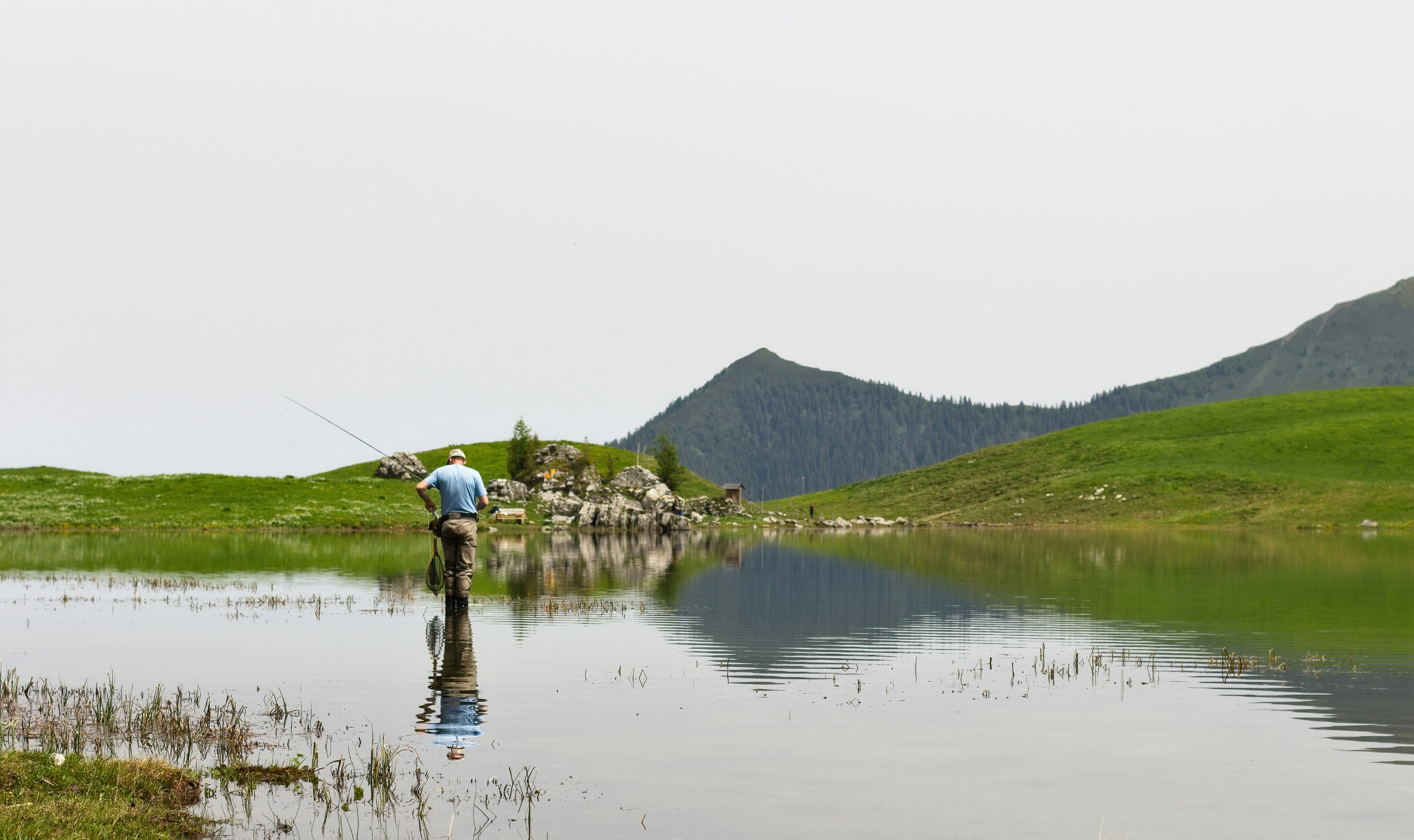 Lone Angler Casting Over a Glassy Flat Beneath Quiet Peaks