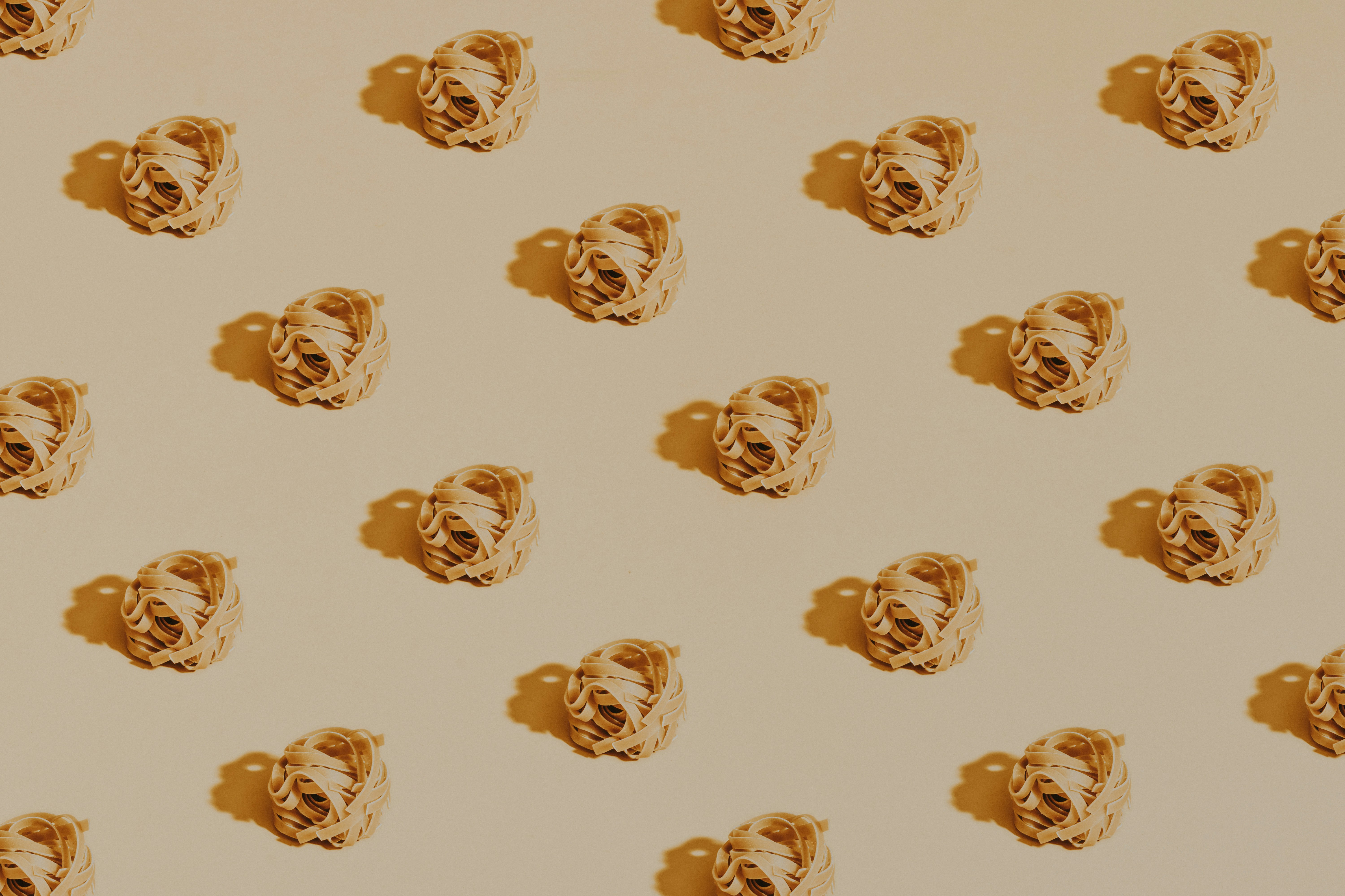 An arrangement of delicate, intertwined pasta nests displayed against a soft, neutral backdrop.