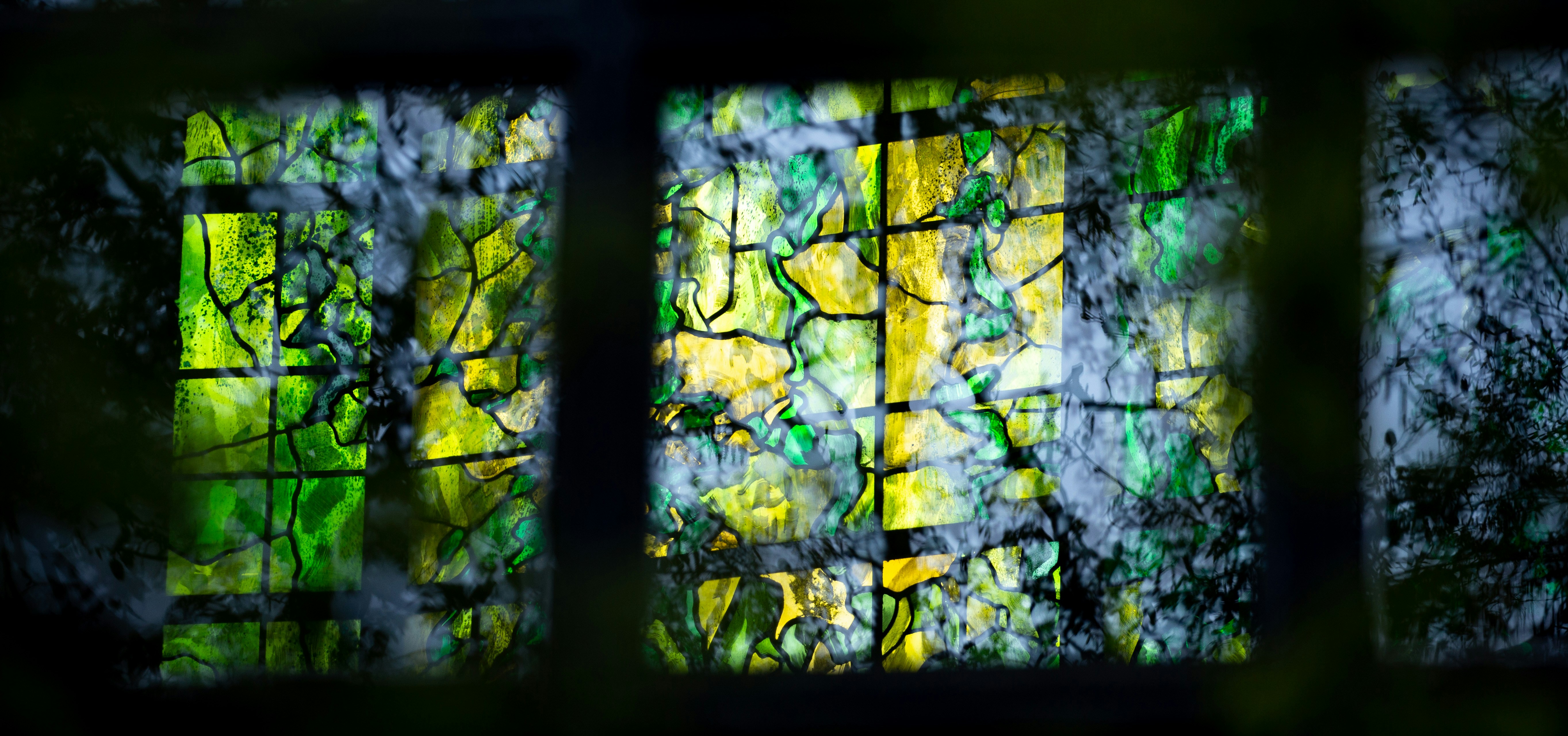 Colorful stained glass window with abstract green and yellow patterns.