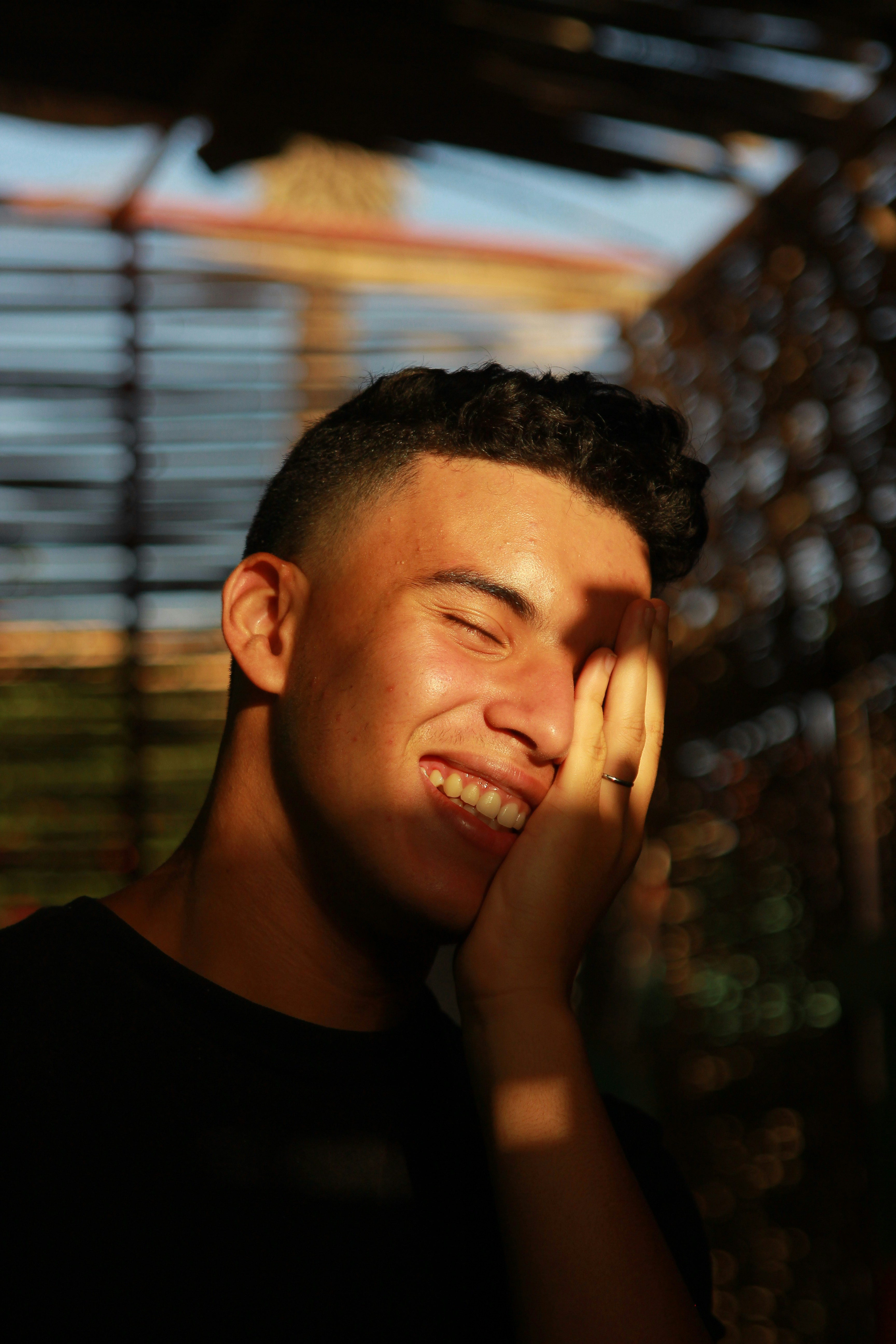Golden Hour Grin: Portrait of a Young Man Beneath Sunlit Fence Lines