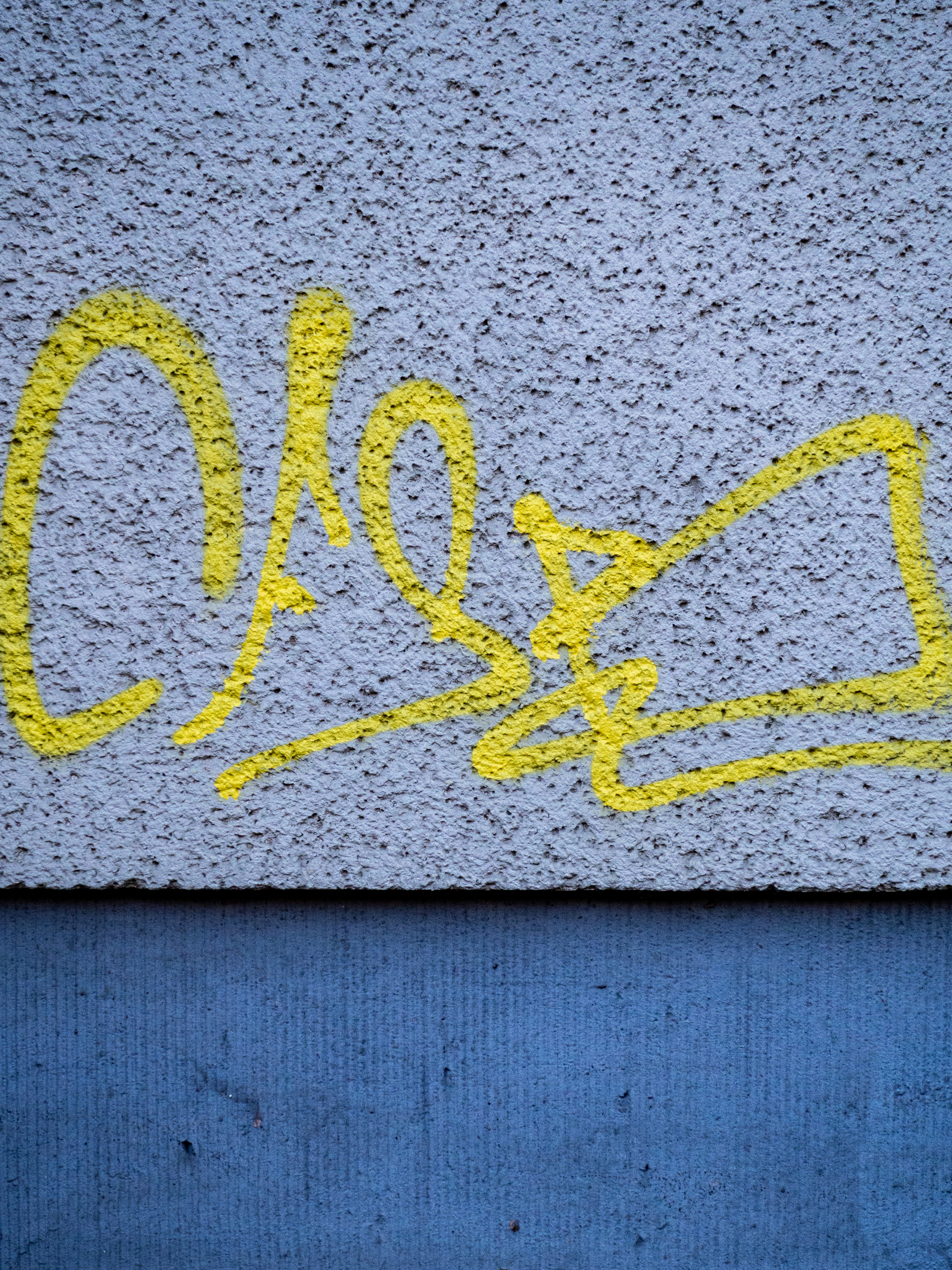 Neon-yellow graffiti knot on a two-tone concrete wall