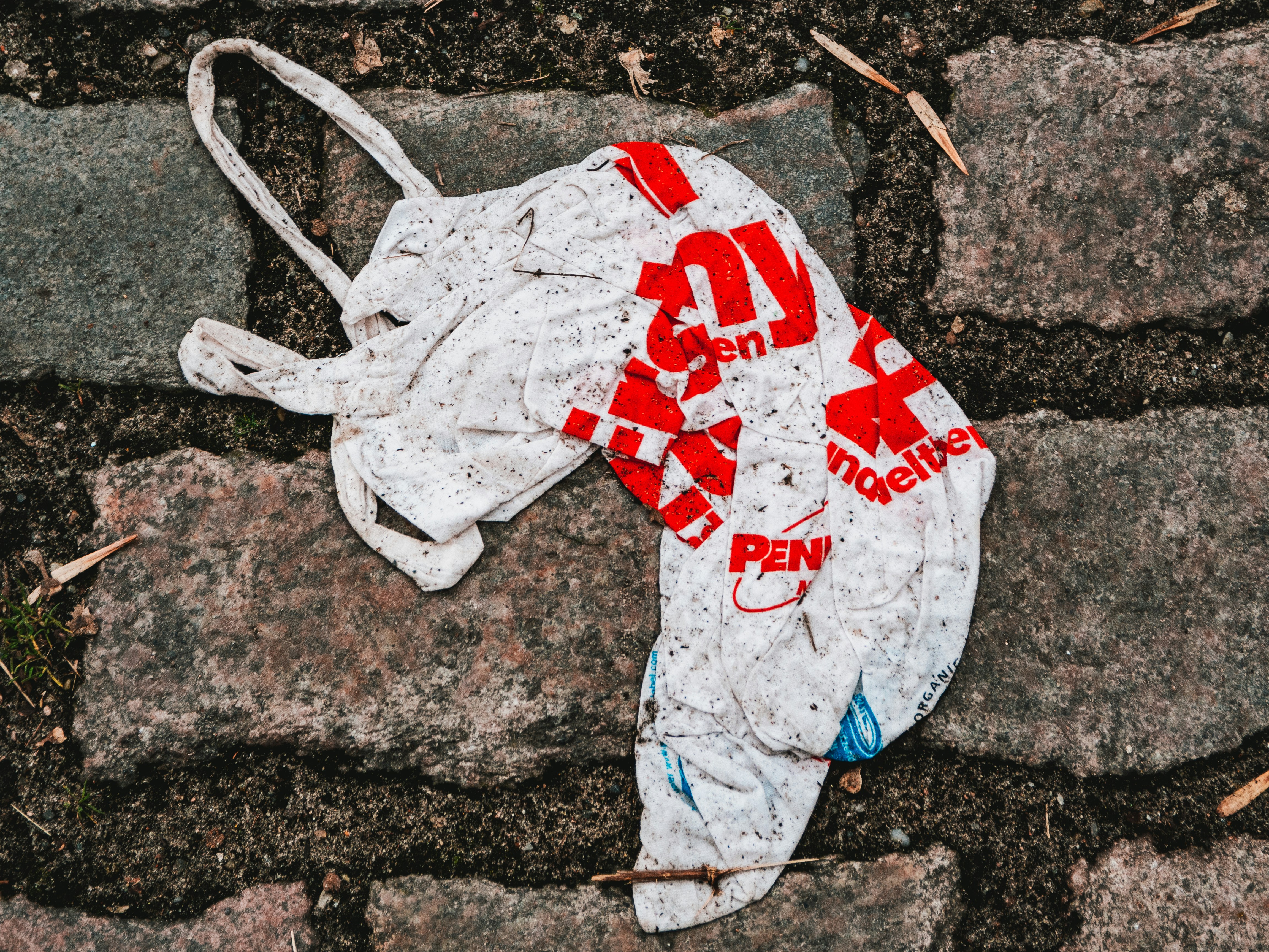 Discarded Plastic Bag with Bold Red Branding on Weathered Cobblestones