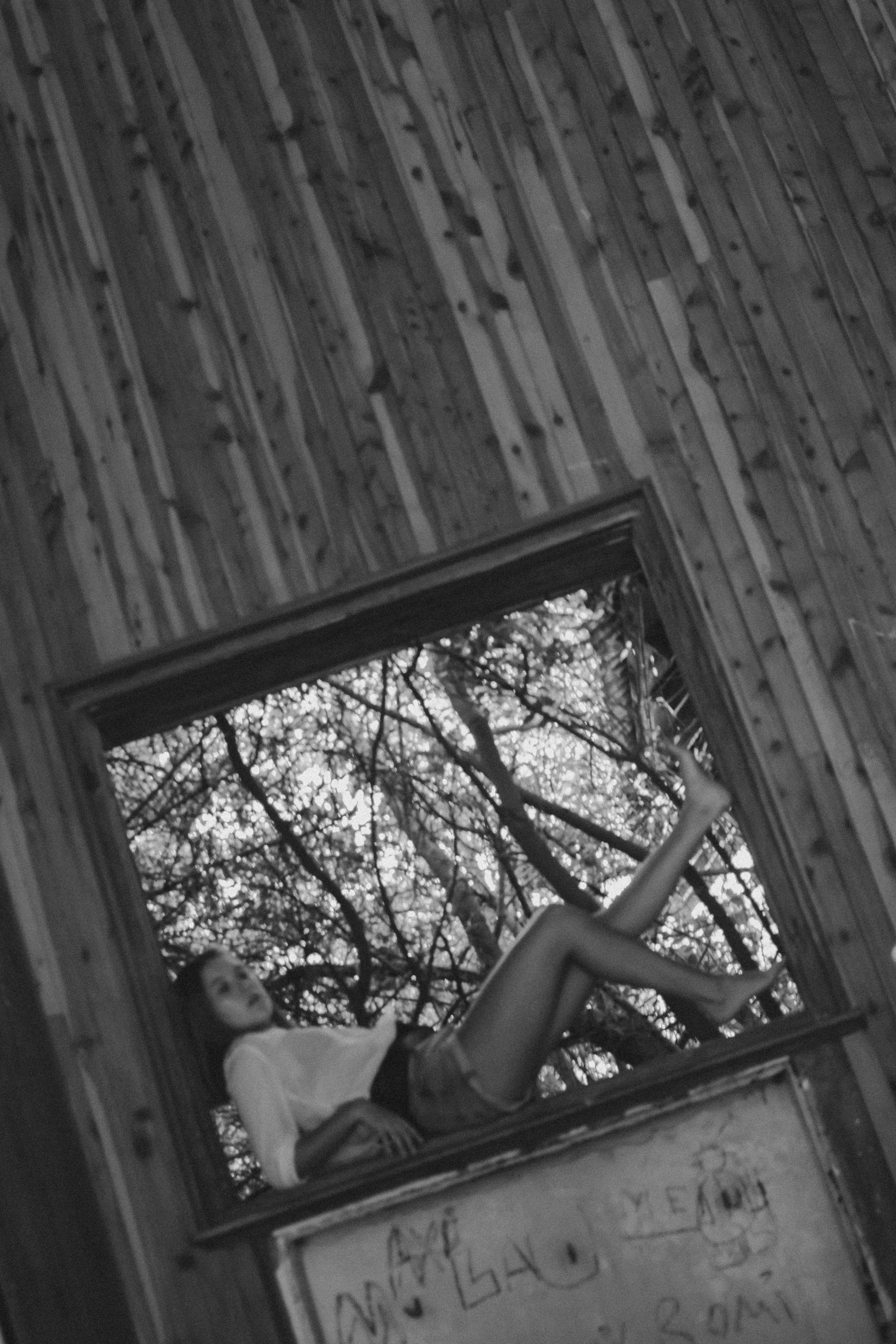 grayscale photo of man and woman in front of wooden wall