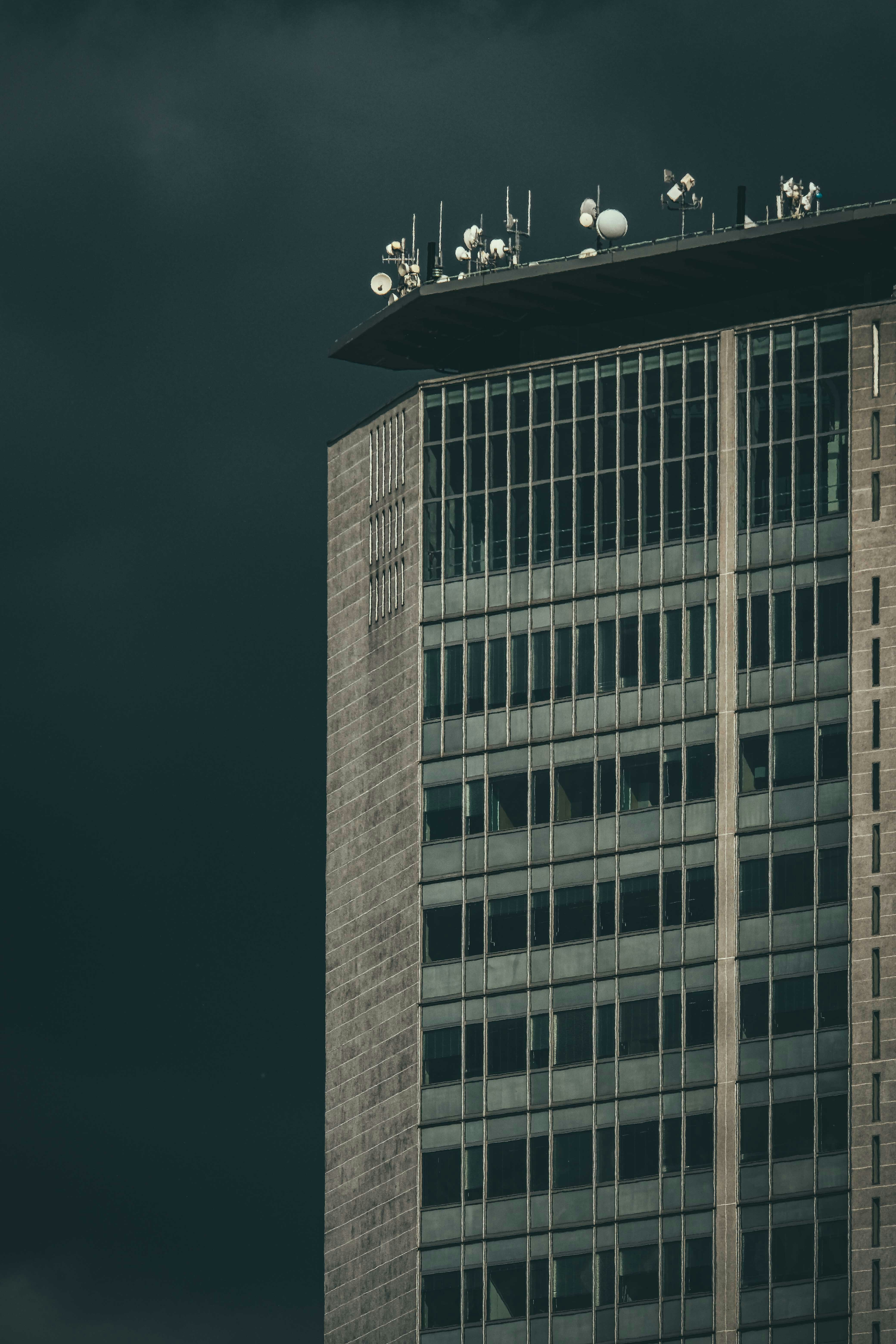 Rooftop Relay: Antenna Cluster on a Teal-Tinted Office Tower