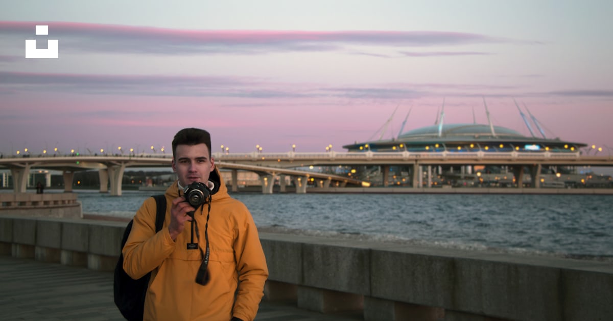 Foto Hombre Con Chaqueta Naranja Sosteniendo Una Cámara Dslr Negra