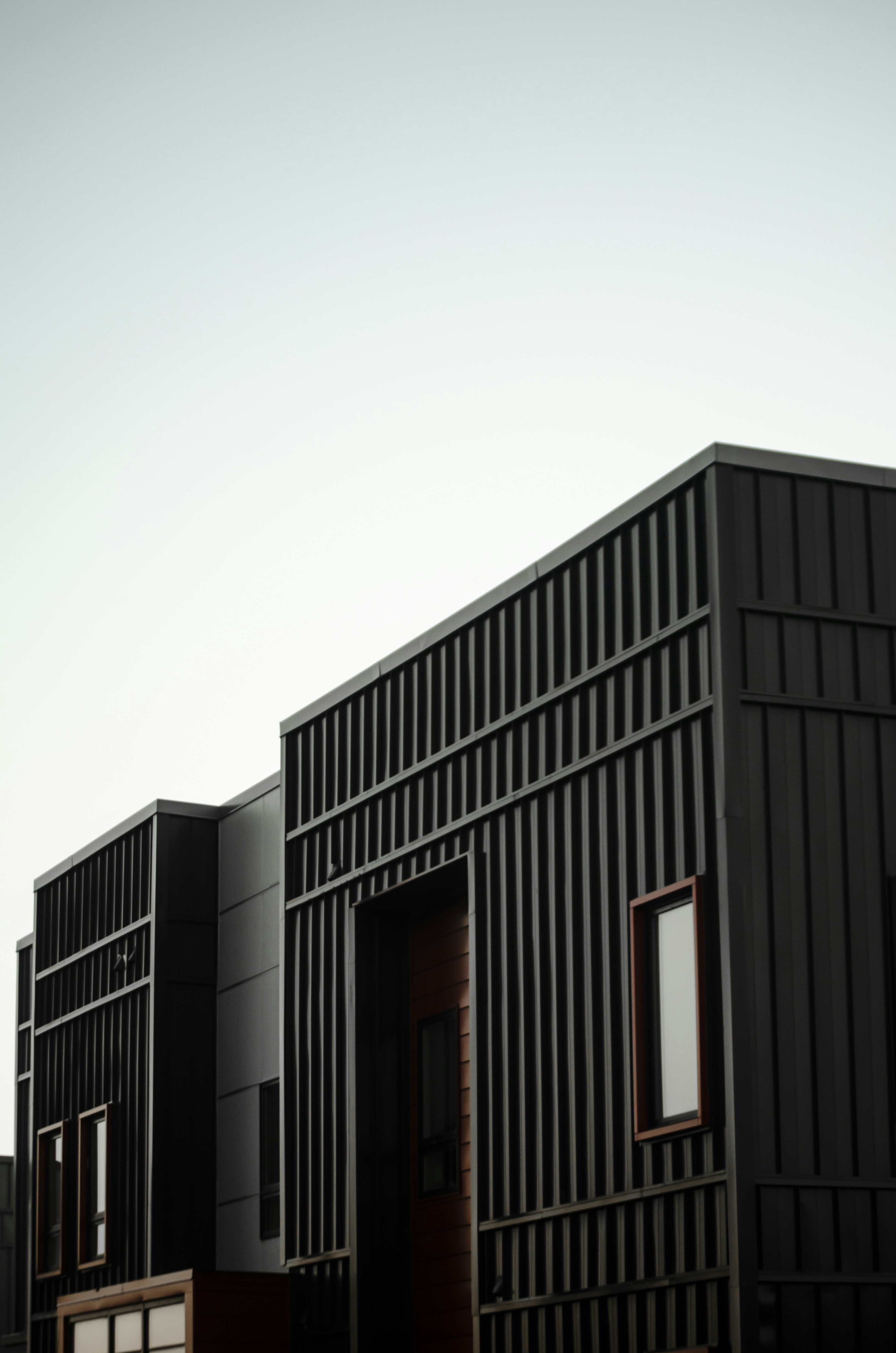 Contemporary building facade showcasing sharp lines and contrasting materials in a minimalist design. The interplay of light and shadow enhances the geometric features.