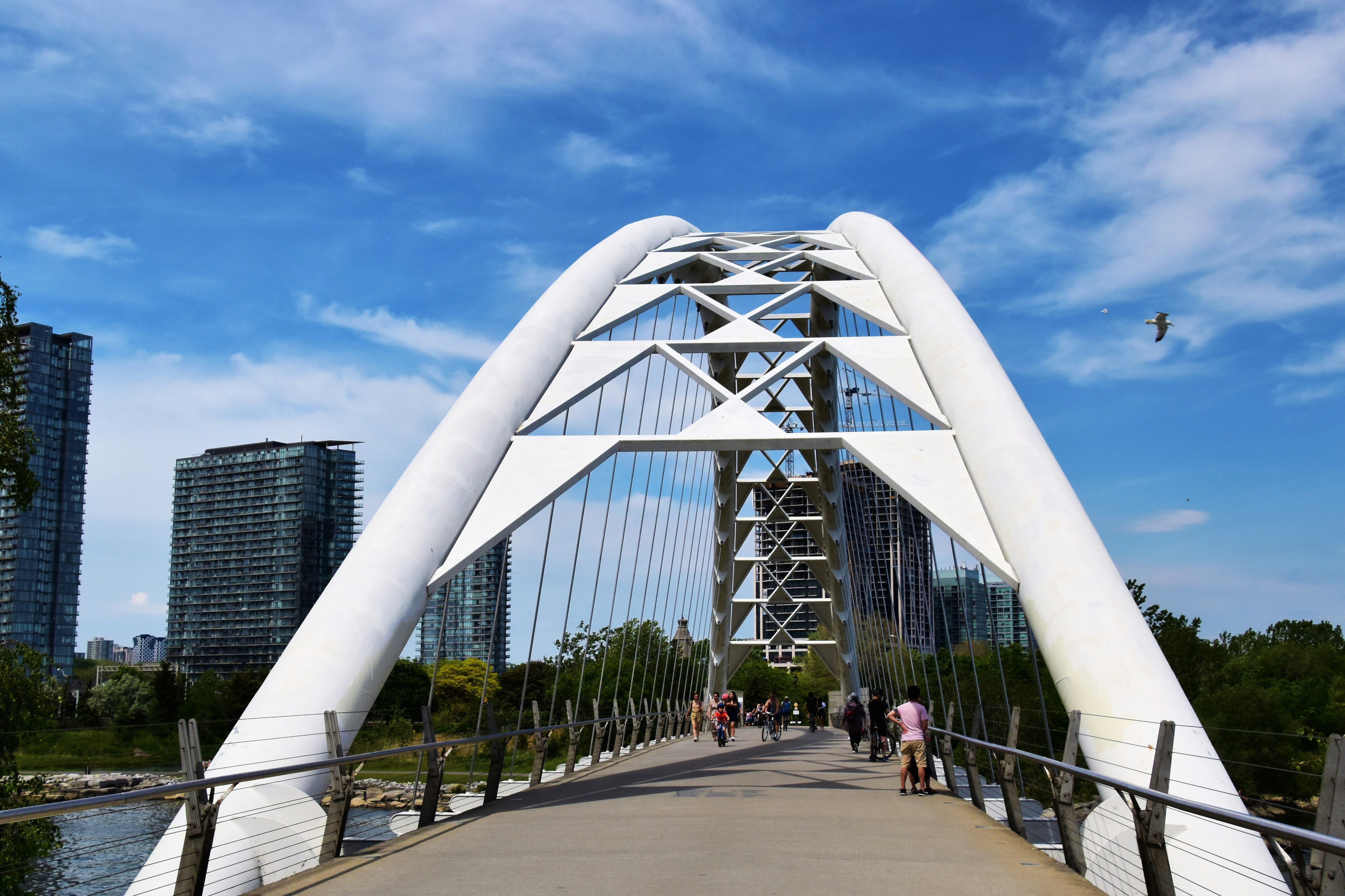 People walking on white concrete bridge under blue sky during daytime ...