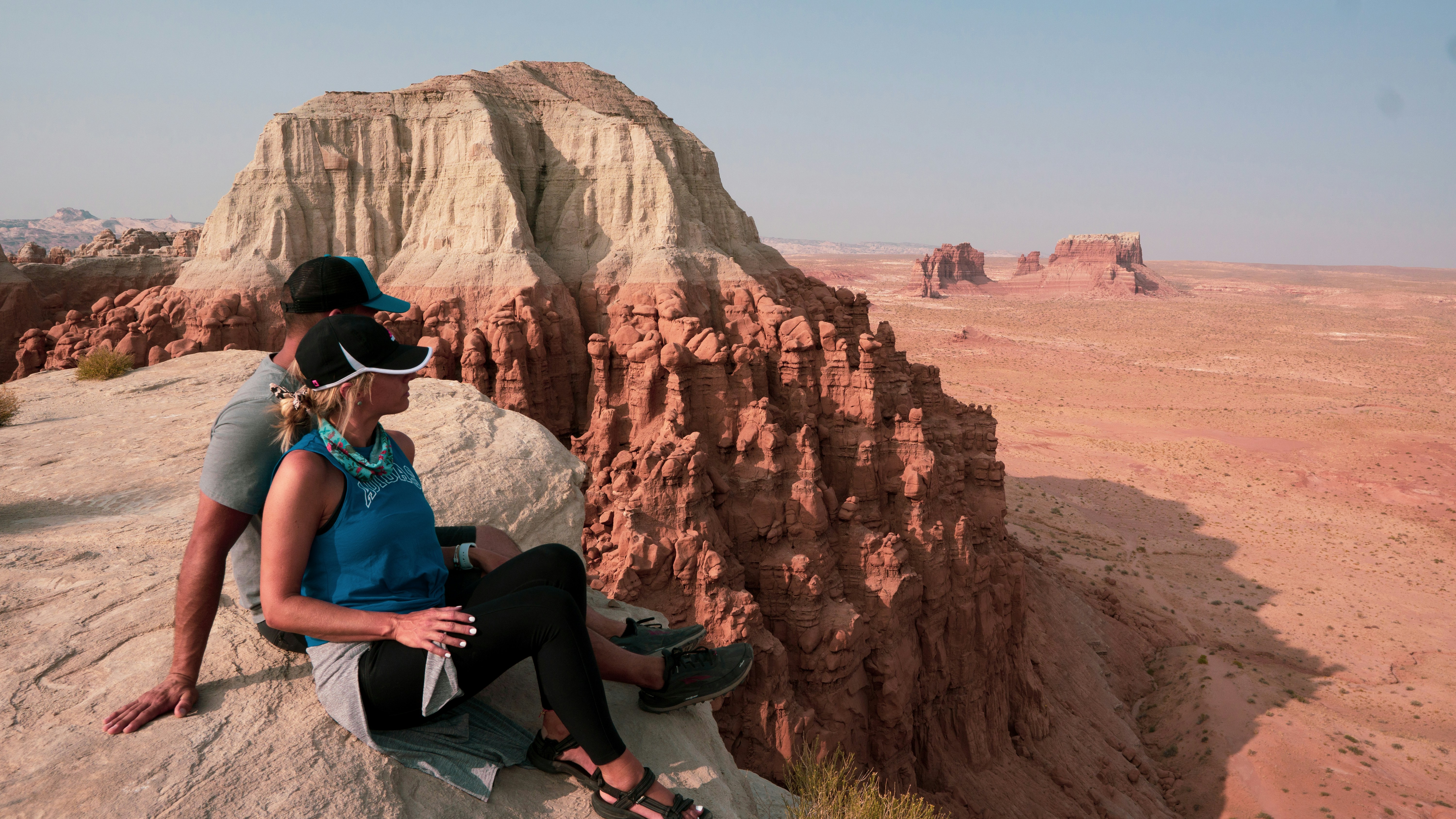 Couple resting on rocks over looking goblin valley in Utah. 
