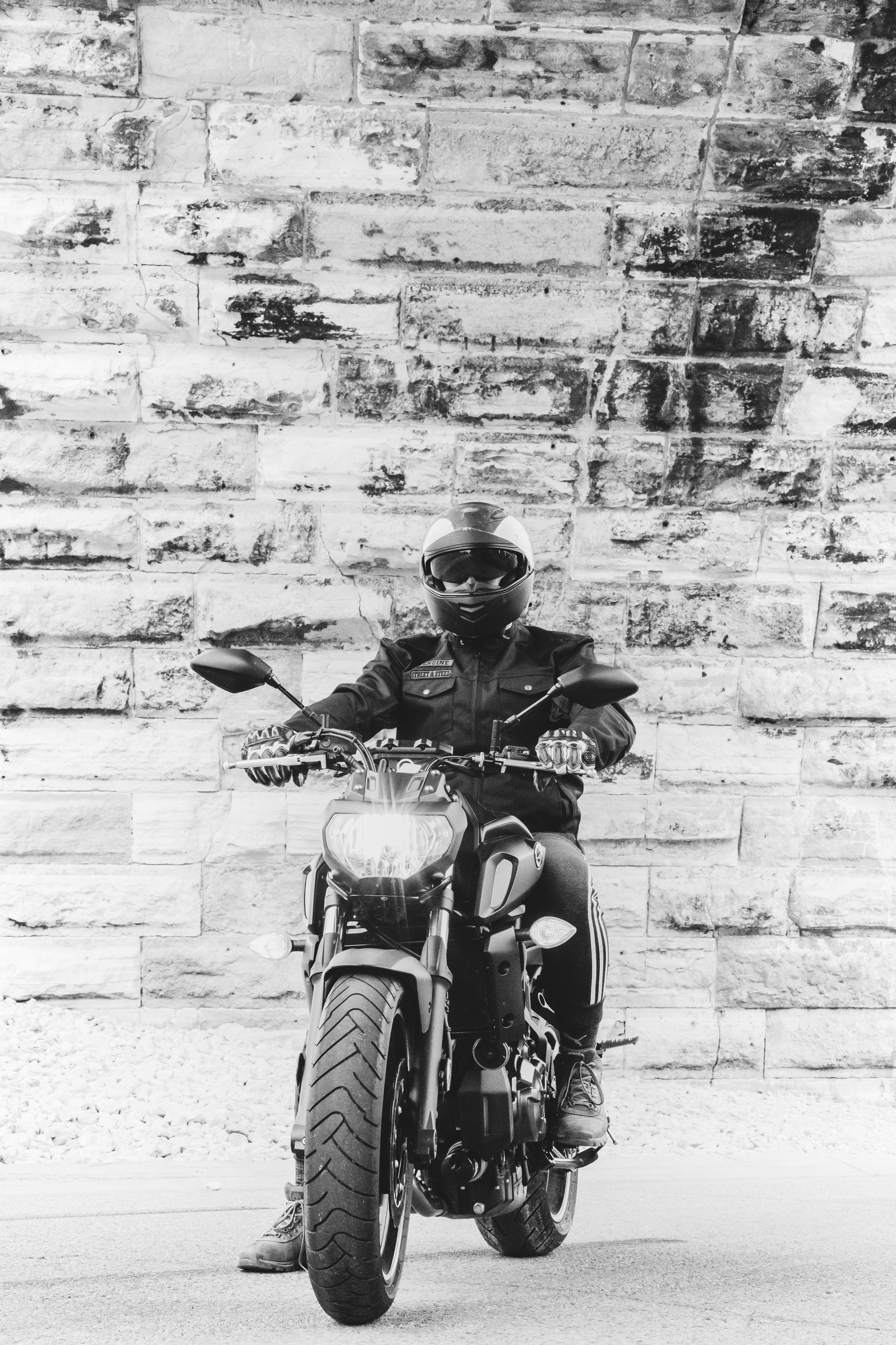 Monochrome Maneuver: Rider Confronts a Weathered Brick Backdrop