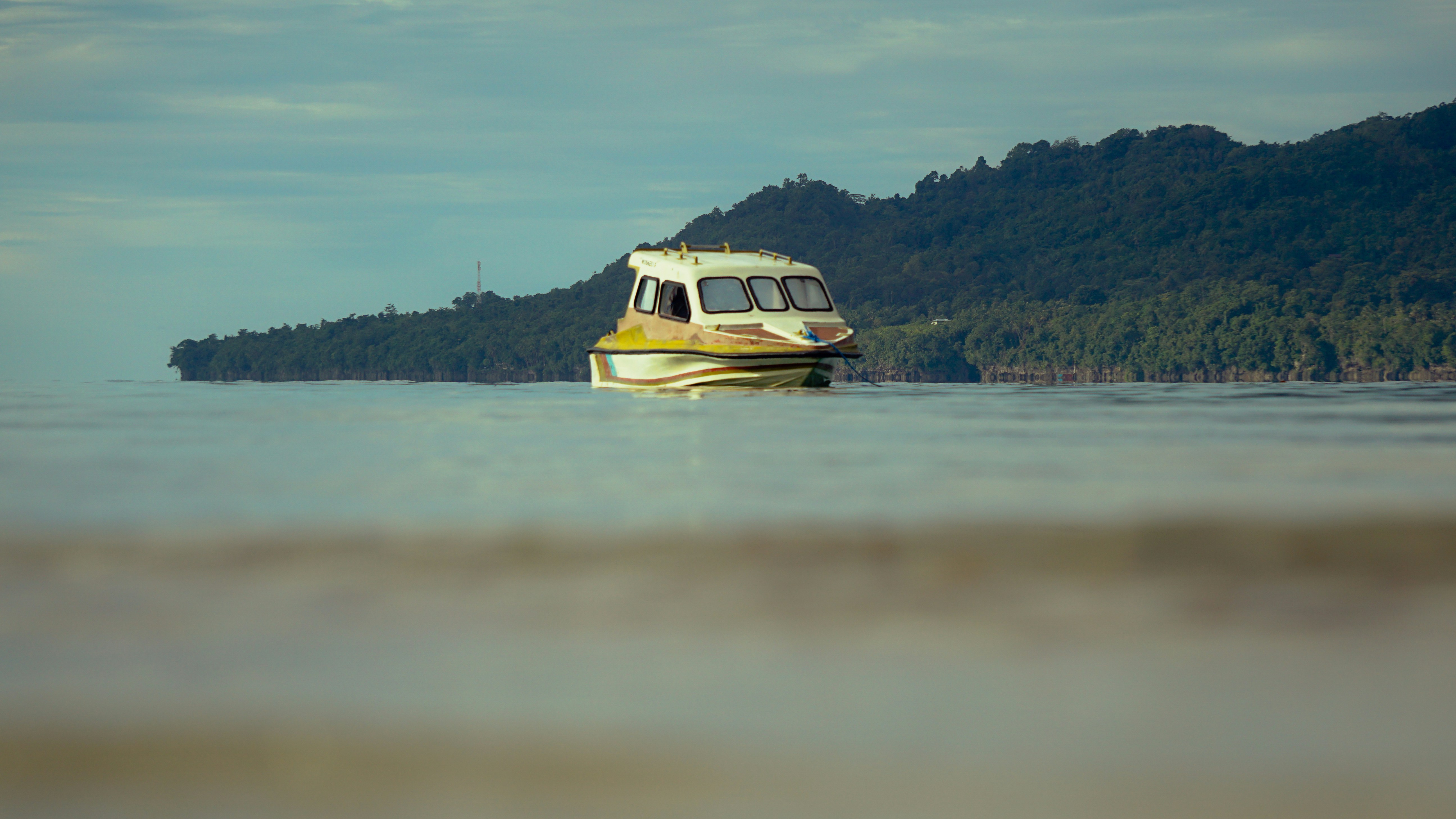 Boat on a calm sea near distant forested hills