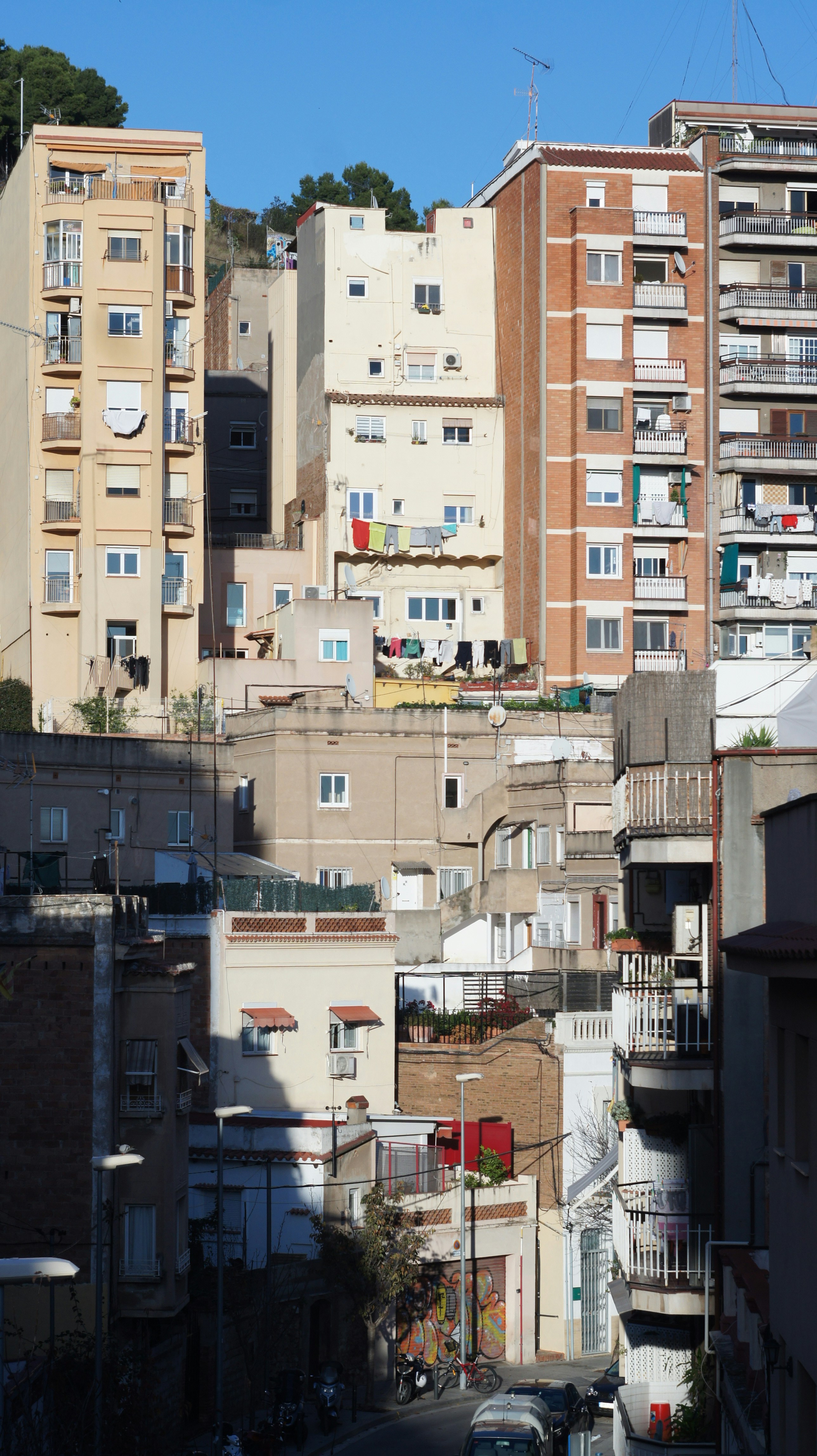 Colorful apartment buildings stacked on a hillside, showcasing laundry hung out to dry against a clear blue sky.