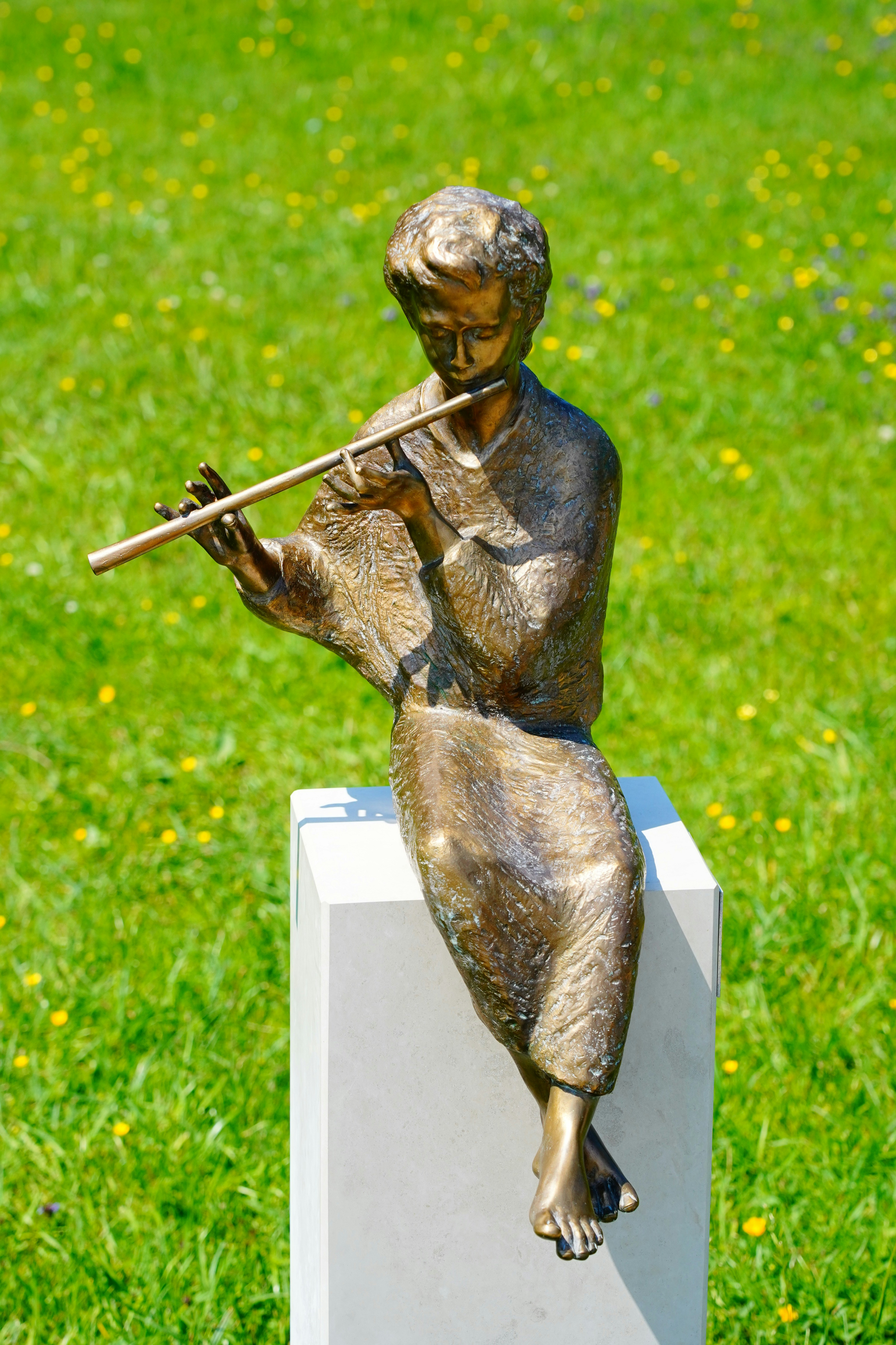 Bronze Flutist on a White Pedestal in a Sunlit Meadow