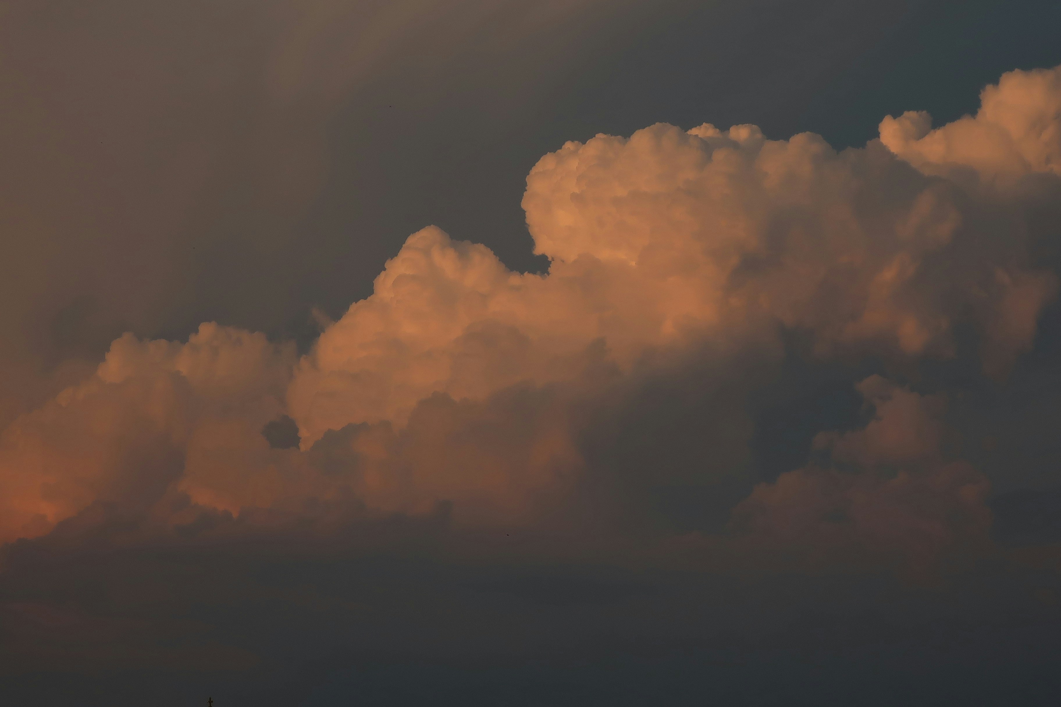 Soft, billowing clouds illuminated by the warm hues of sunset against a darkening backdrop.